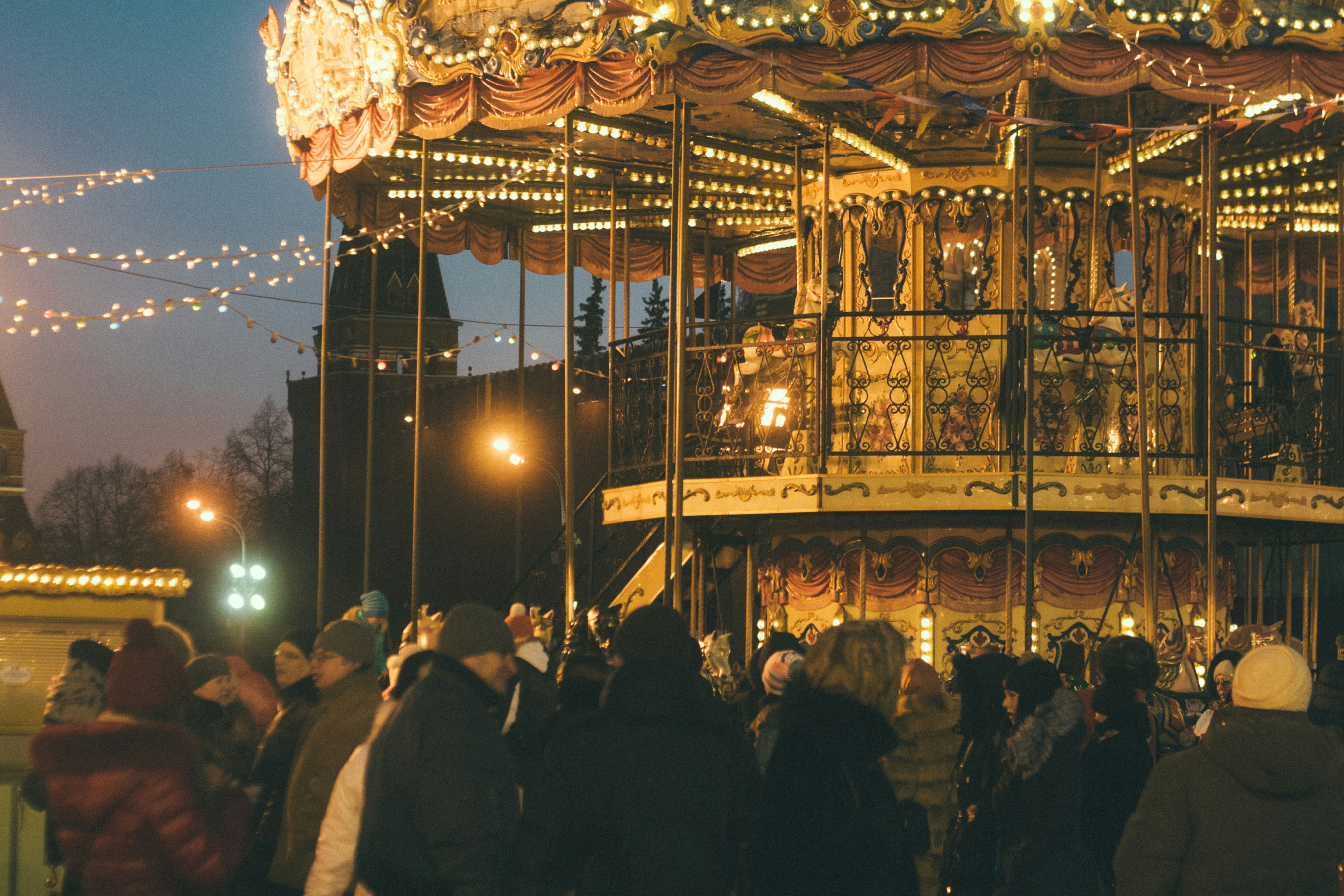 A group of people standing around a merry go round photo – Free Red ...