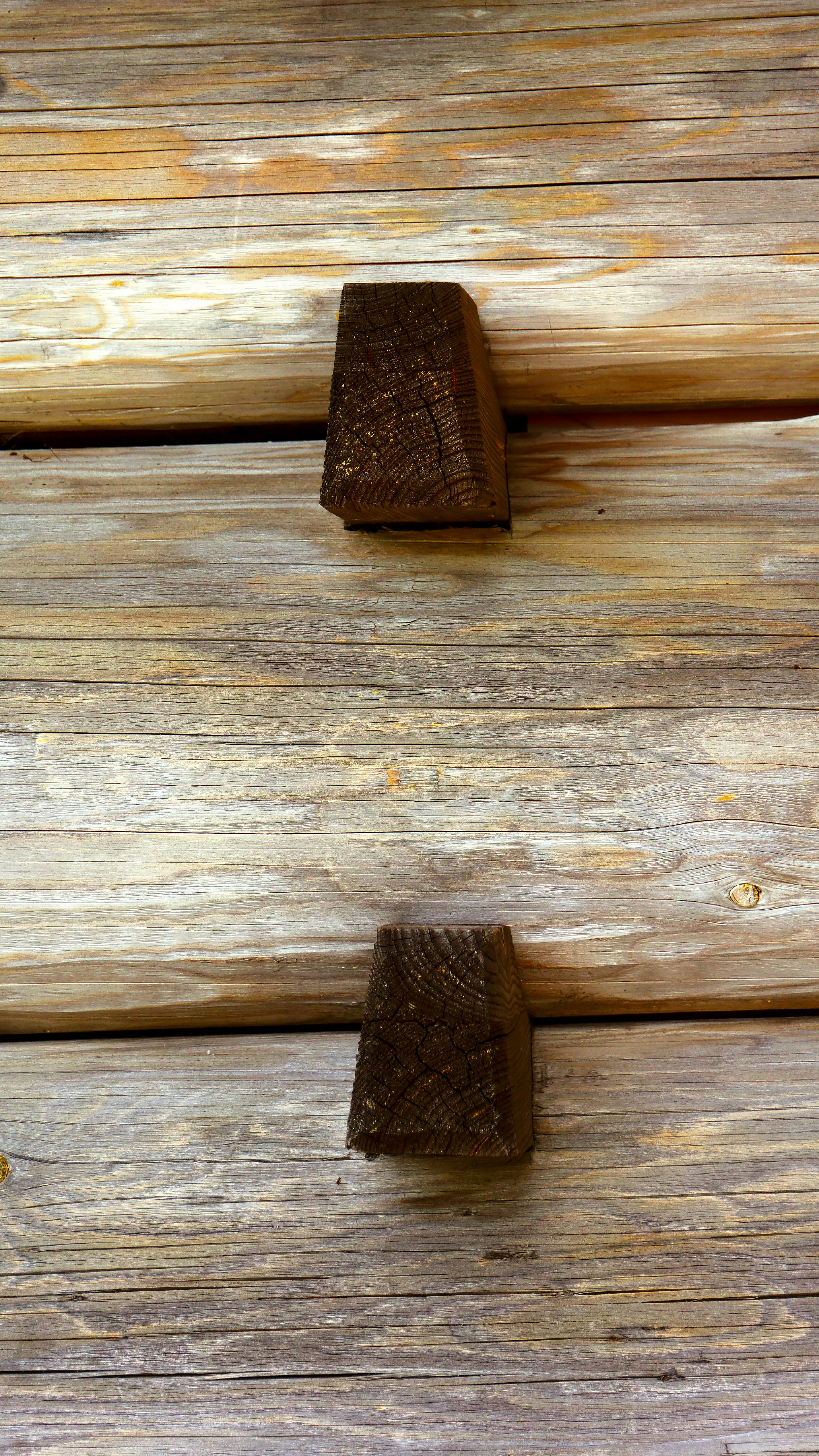 Two wooden blocks resting on a weathered wooden surface, showcasing the natural grain and texture of the materials.