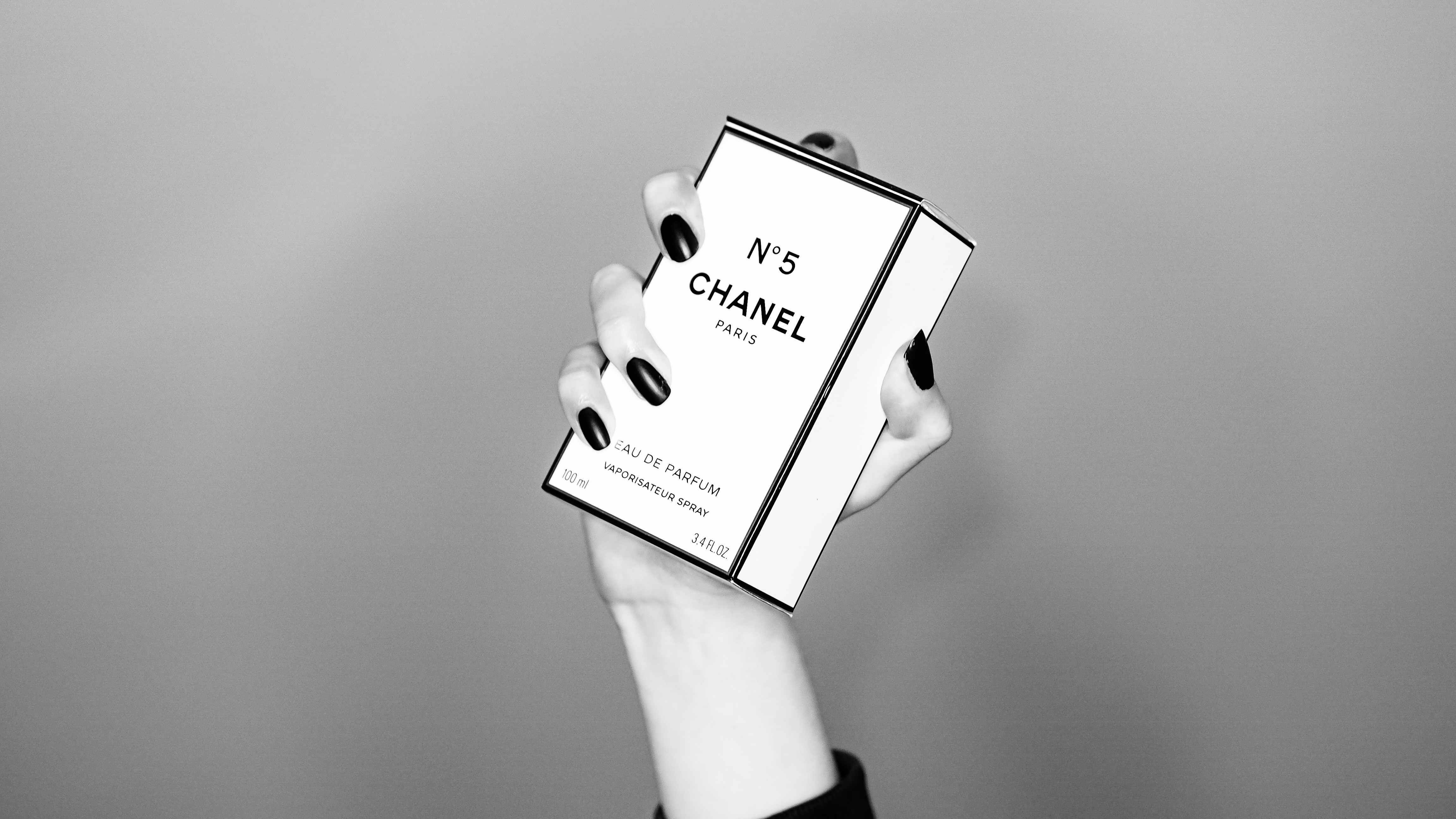 A woman holding up a box with a chanel logo on it photo – Free White ...