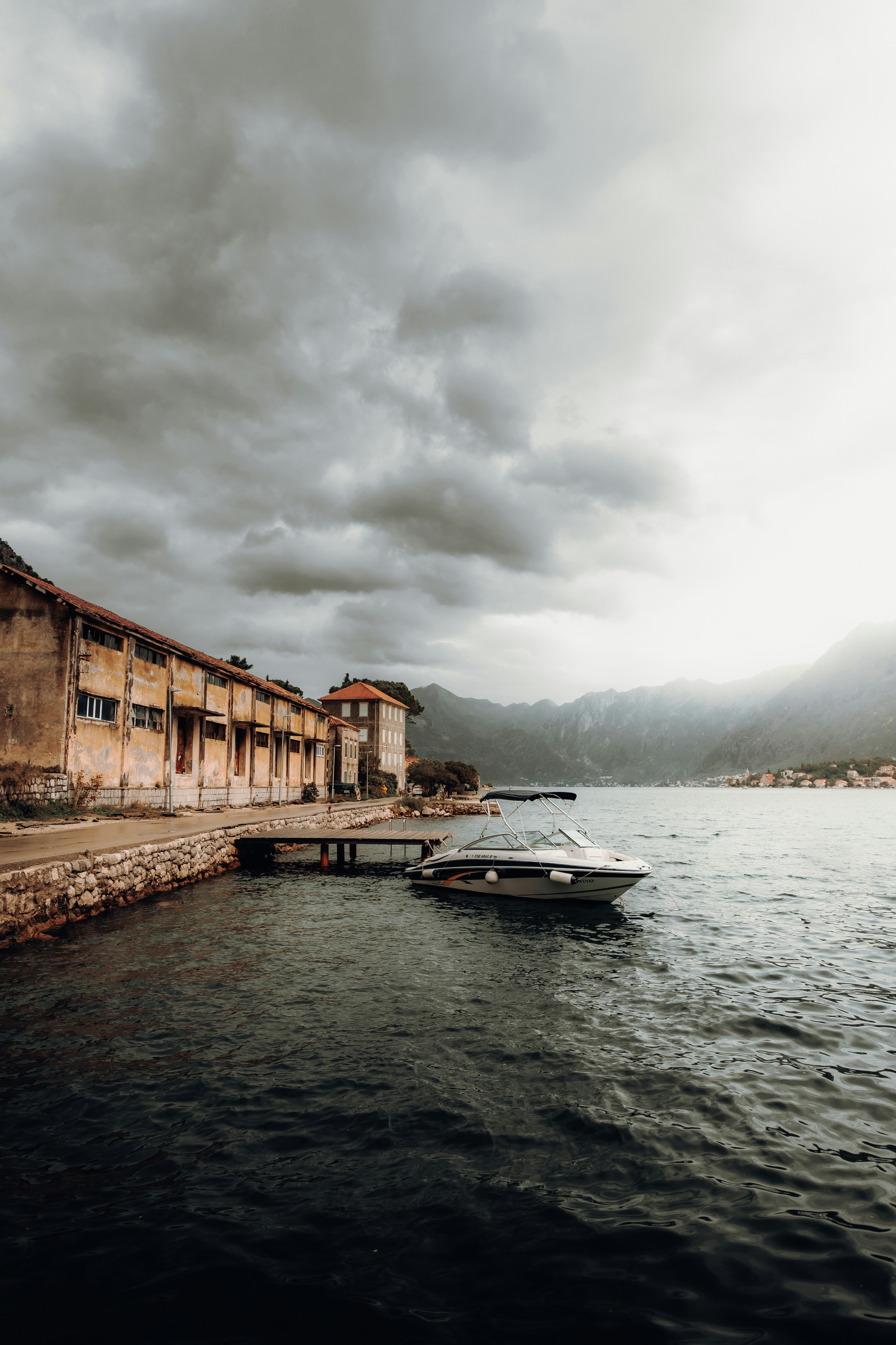 Moored Elegy: Boat at a Weathered Wharf Against a Looming Cloudscape