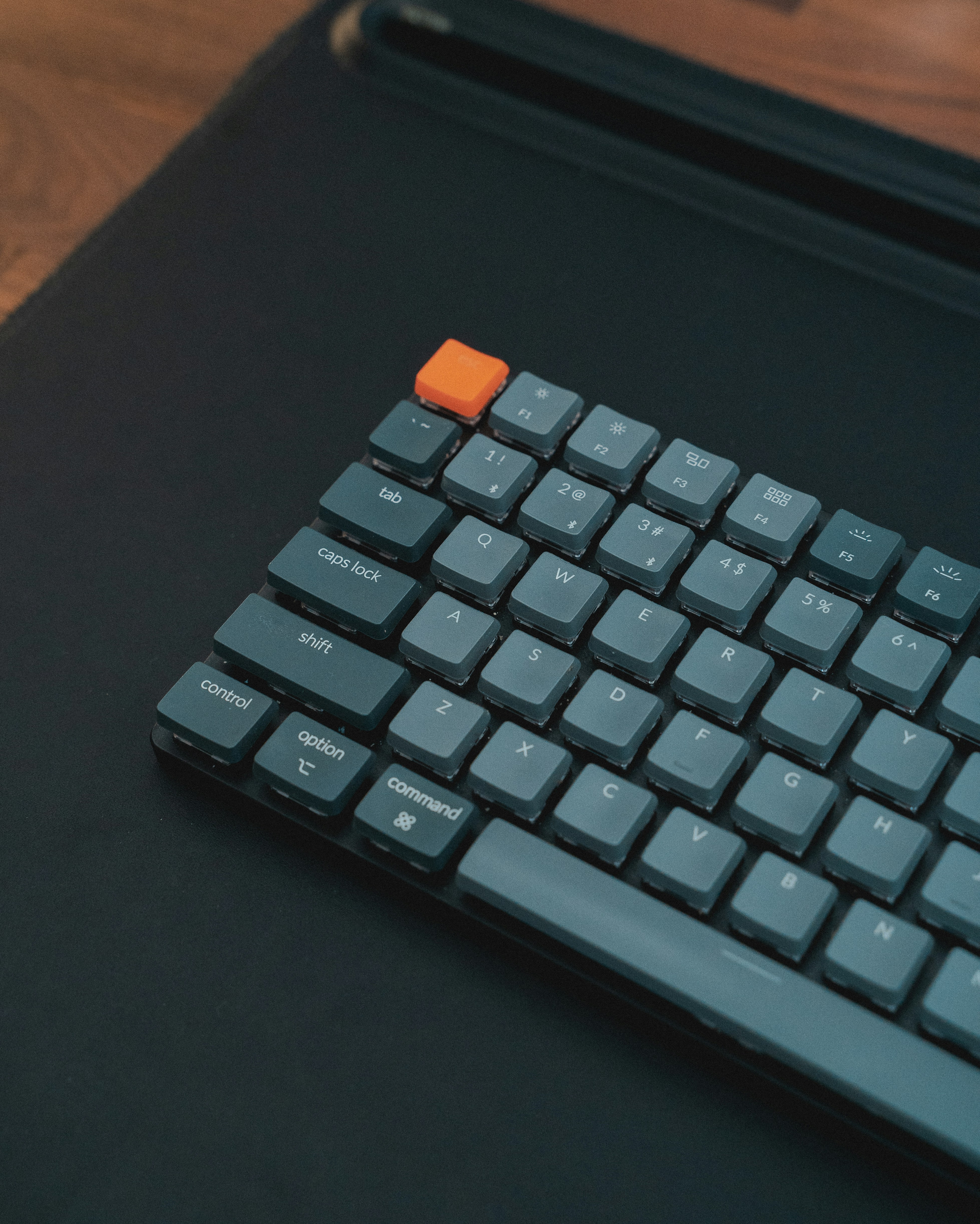 Close-up of a sleek keyboard on a dark surface, featuring a standout orange key among monochrome keys.