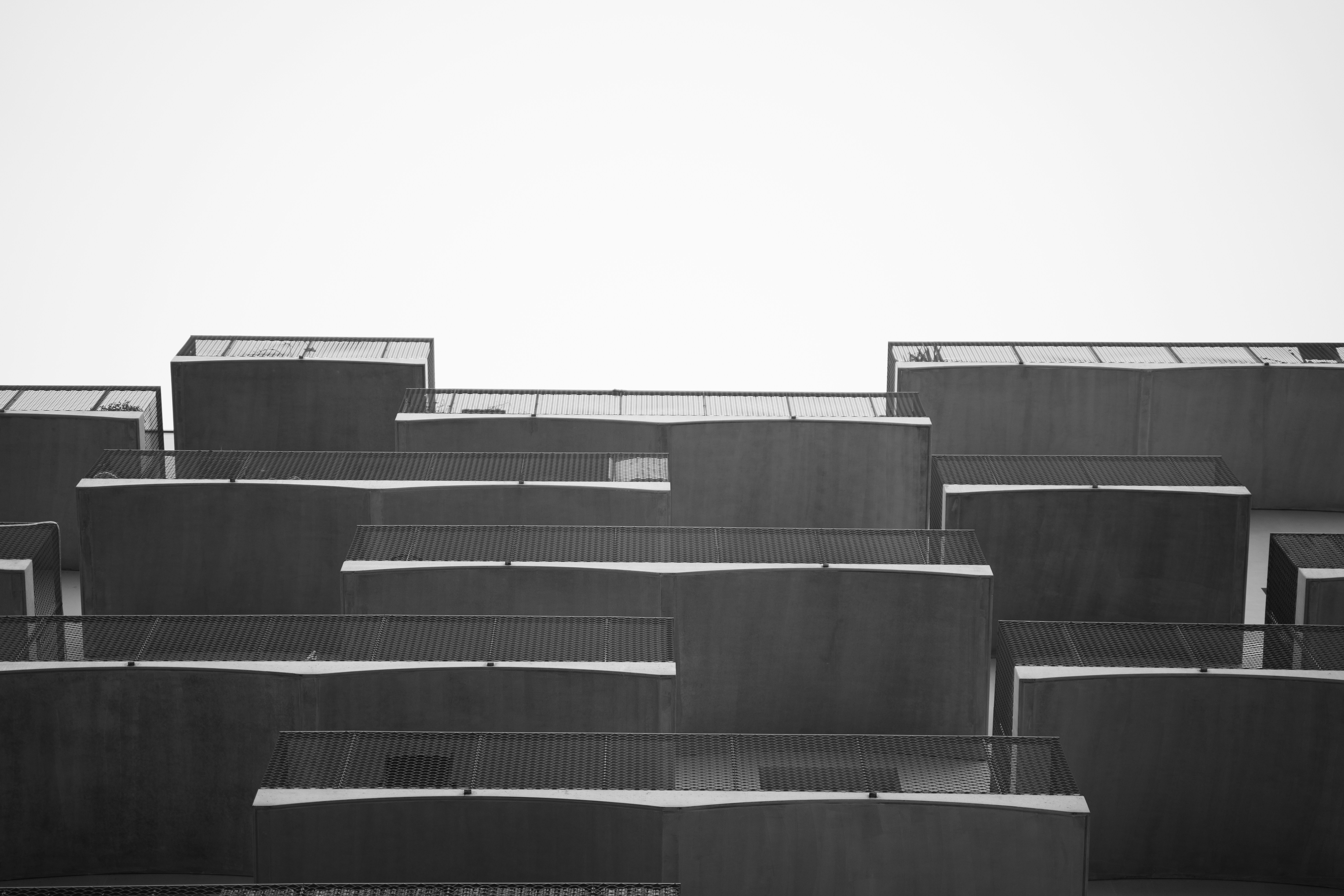 Black and white architectural photograph of staggered balconies against a pale sky.