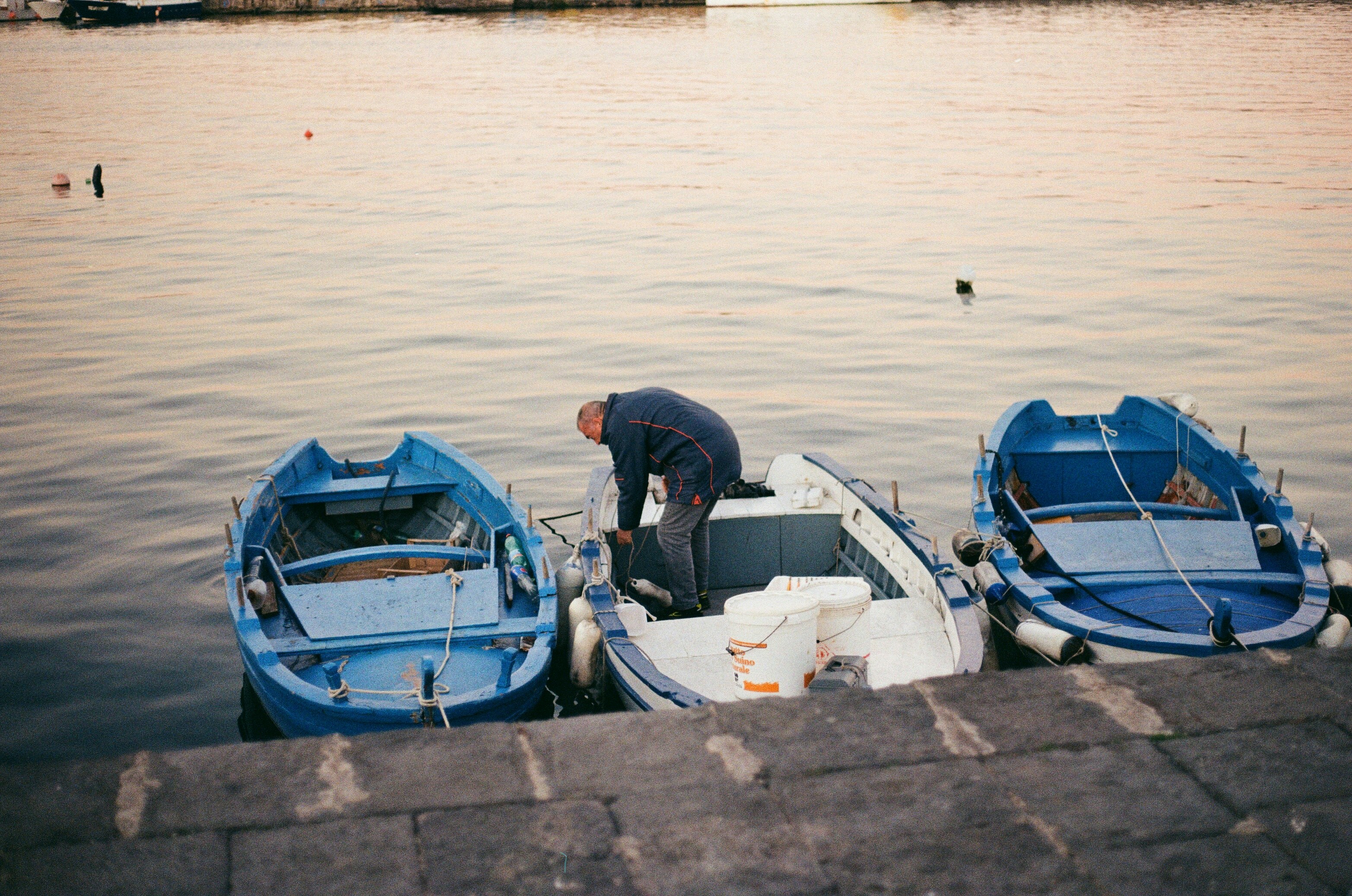 A man standing next to two small boats photo – Free Sicilia Image on ...