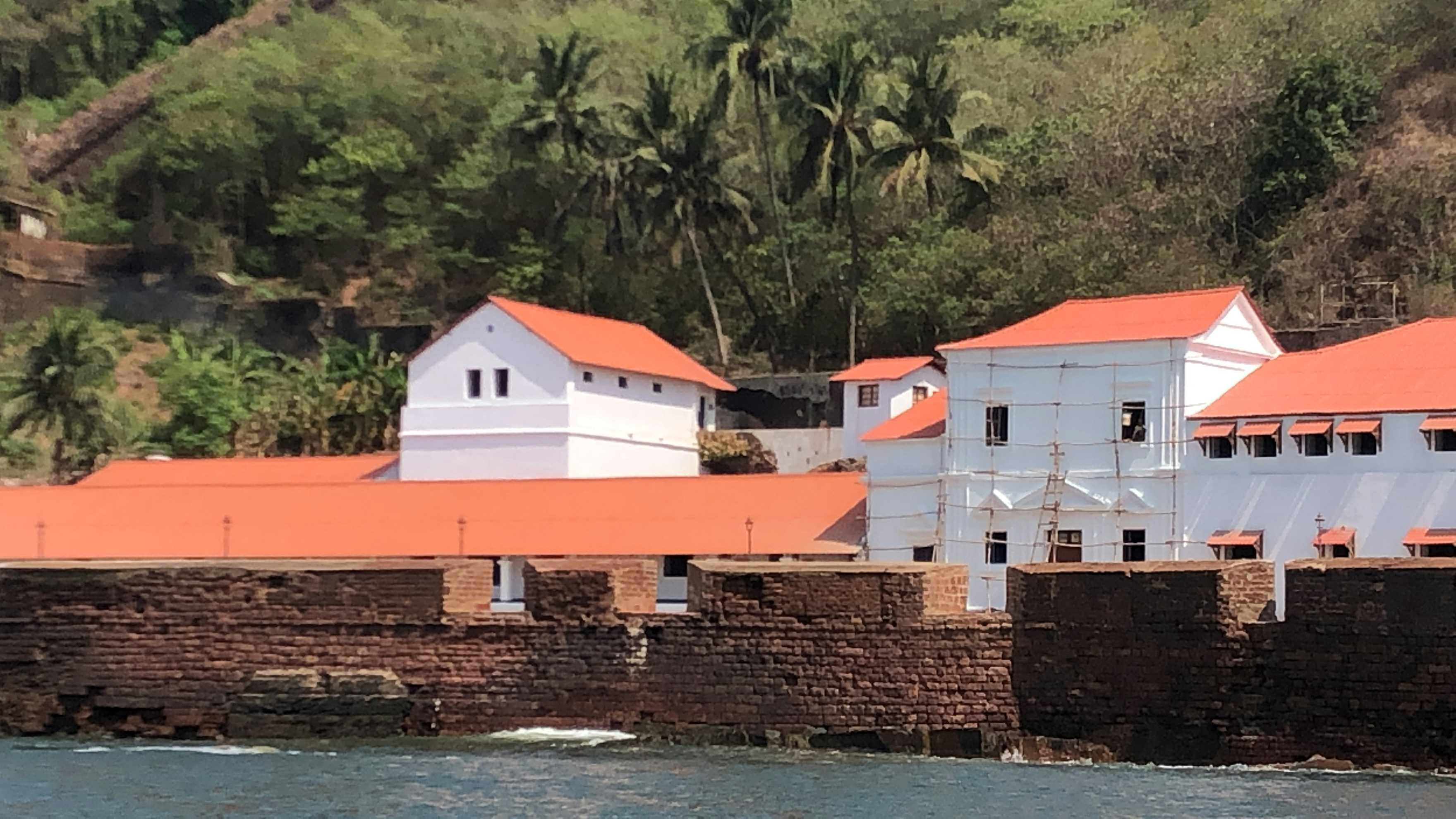 A white building with a red roof next to a body of water photo – Free ...