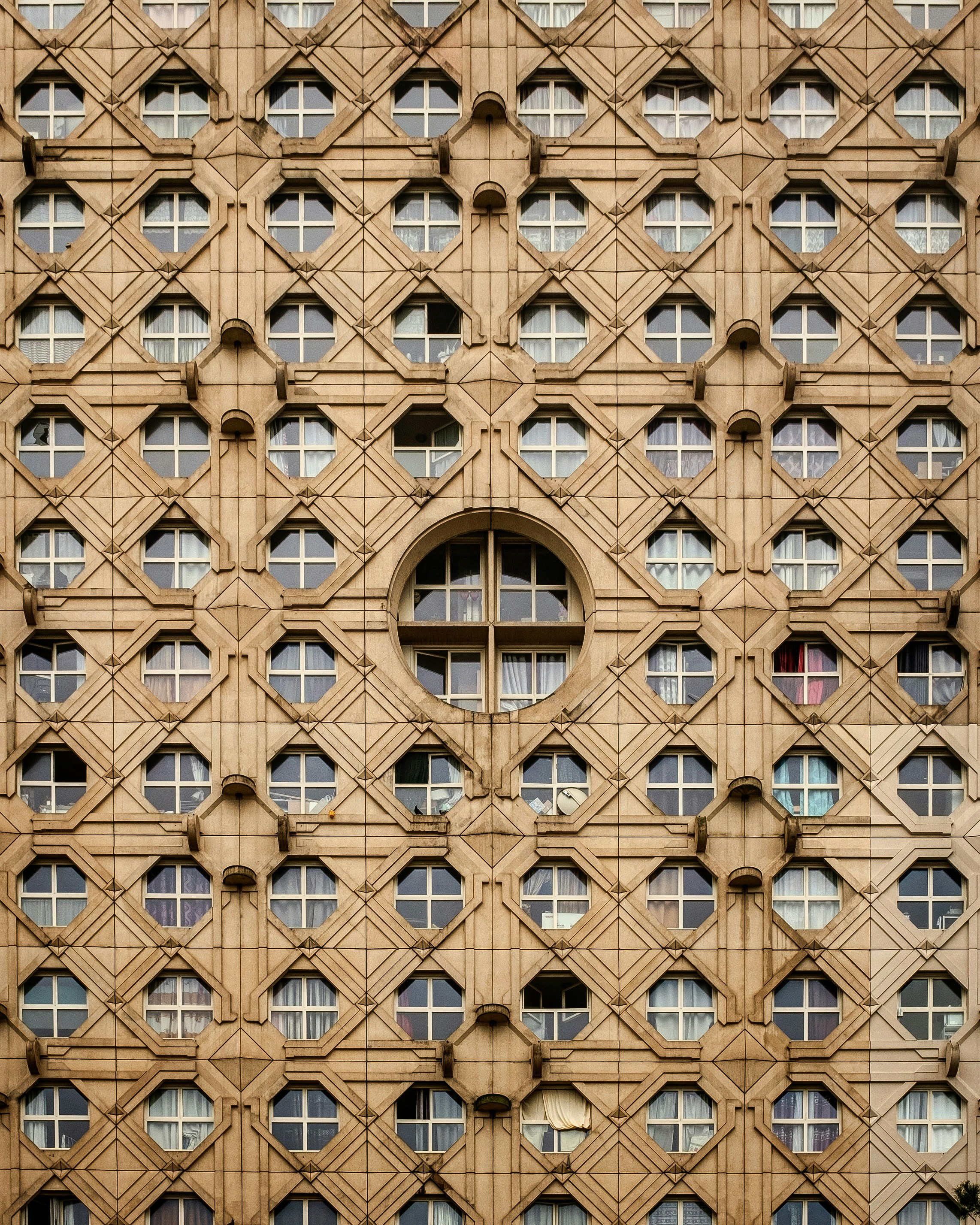 Architectural facade featuring a rhythmic pattern of windows and geometric shapes, highlighted by a central circular window.