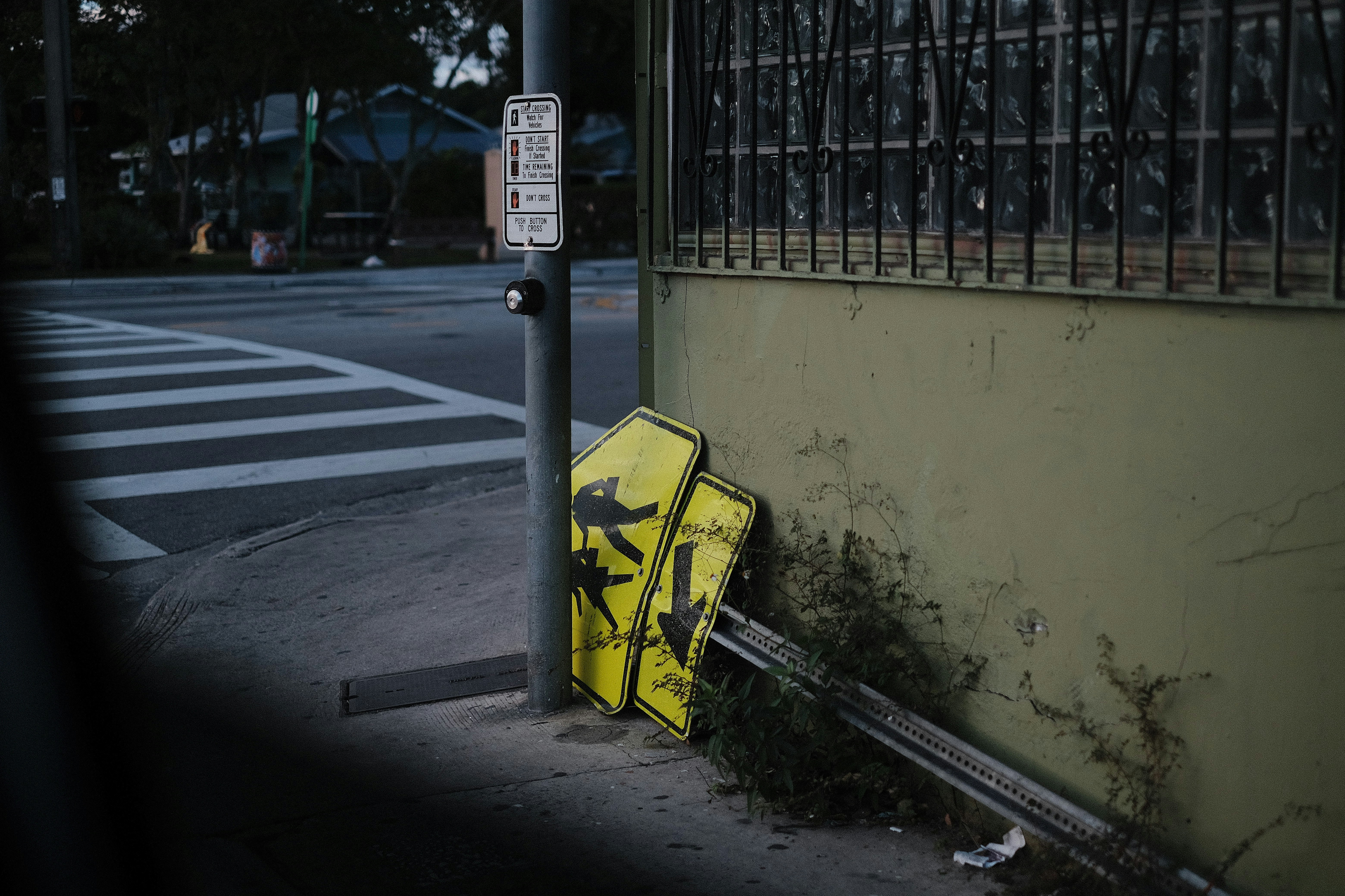 Leaning Yellow Caution Signs by a Mossy Wall at Dusk