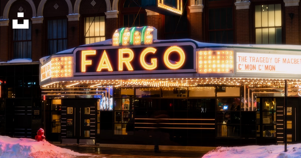 A Theater Marquee Lit Up At Night With Snow On The Ground Photo Free