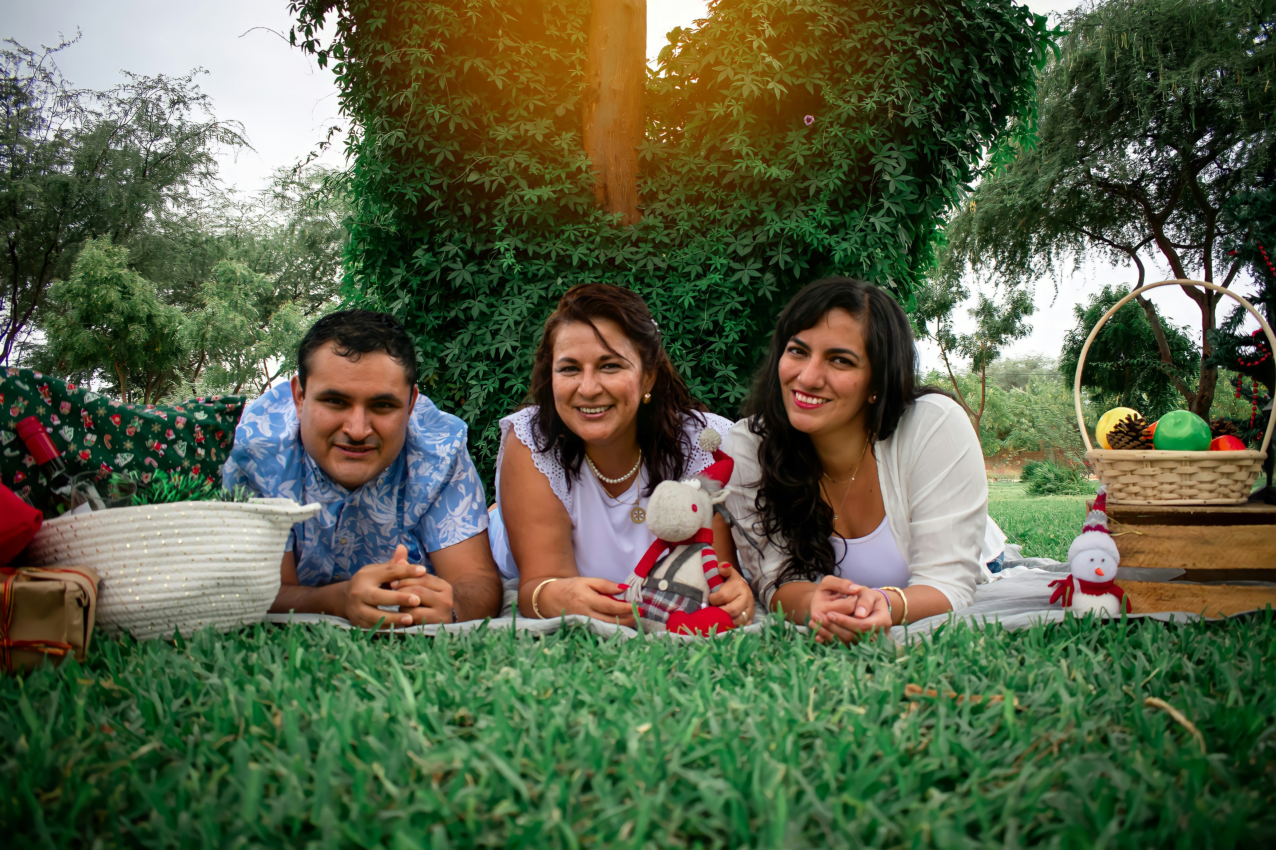 Sunlit Park Portrait: Three Friends and a Plush Bear in a Lush Picnic