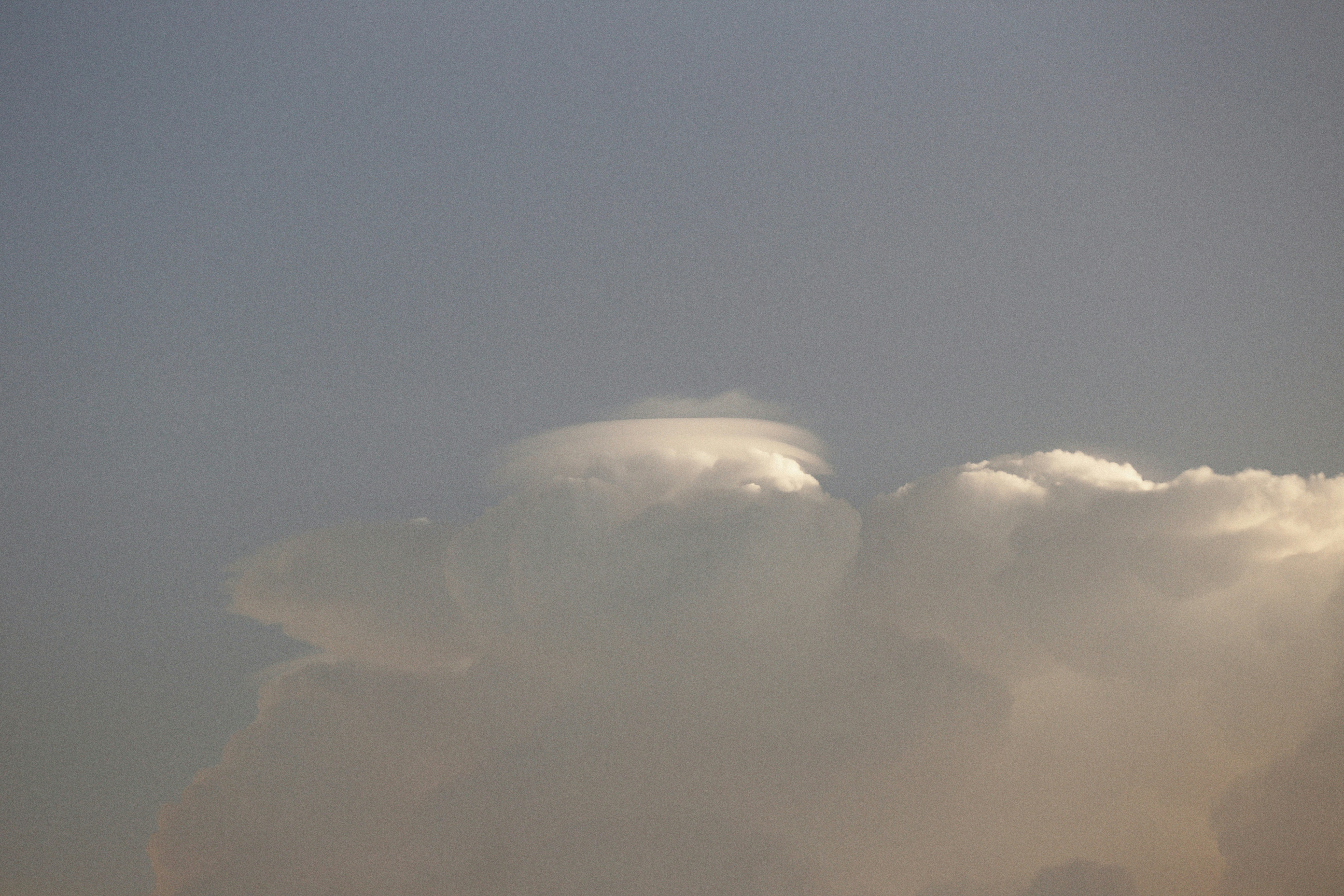 a plane flying in the sky with a cloud in the background