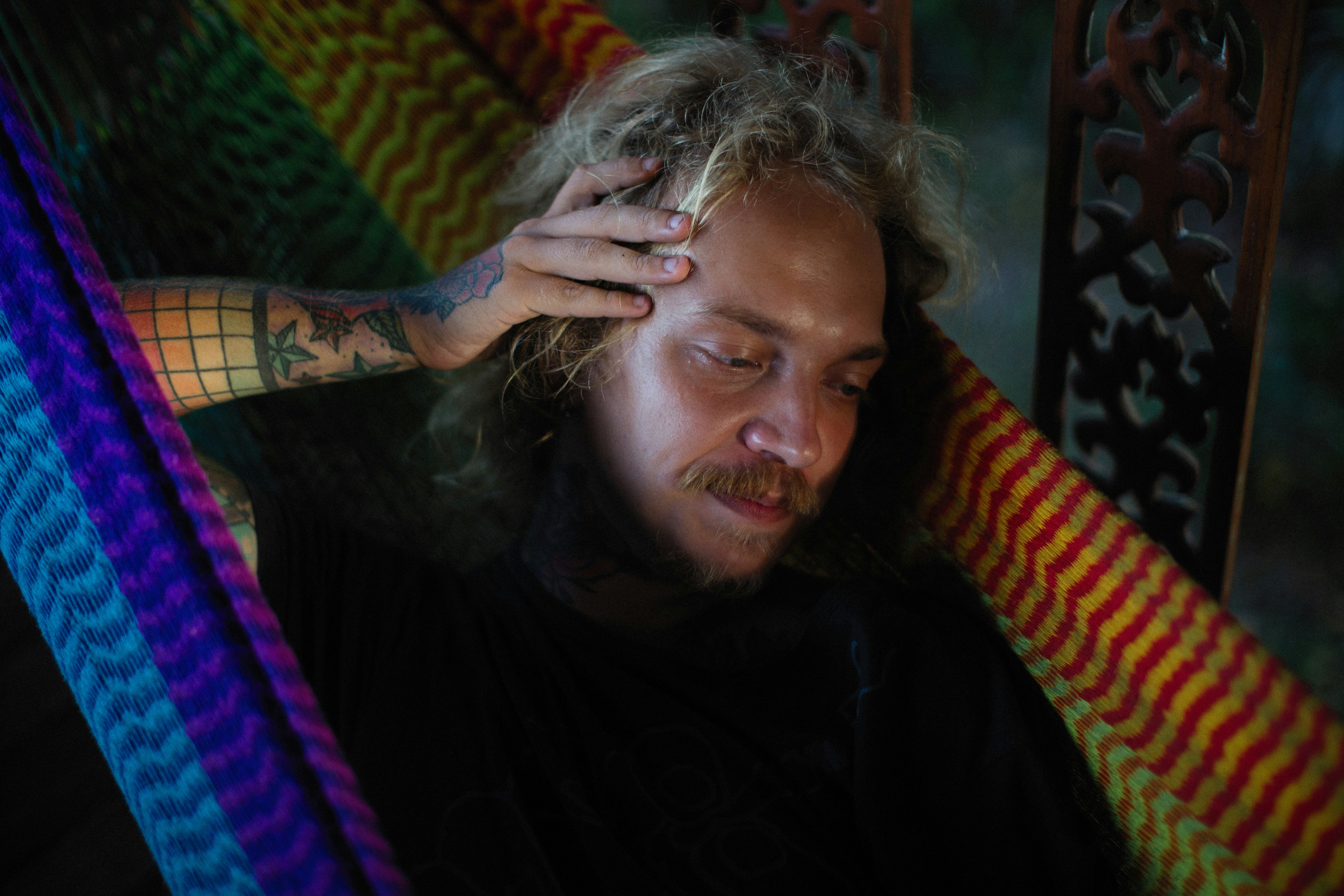 A man with a tattoo on his arm sitting in a hammock photo – Free Skin ...