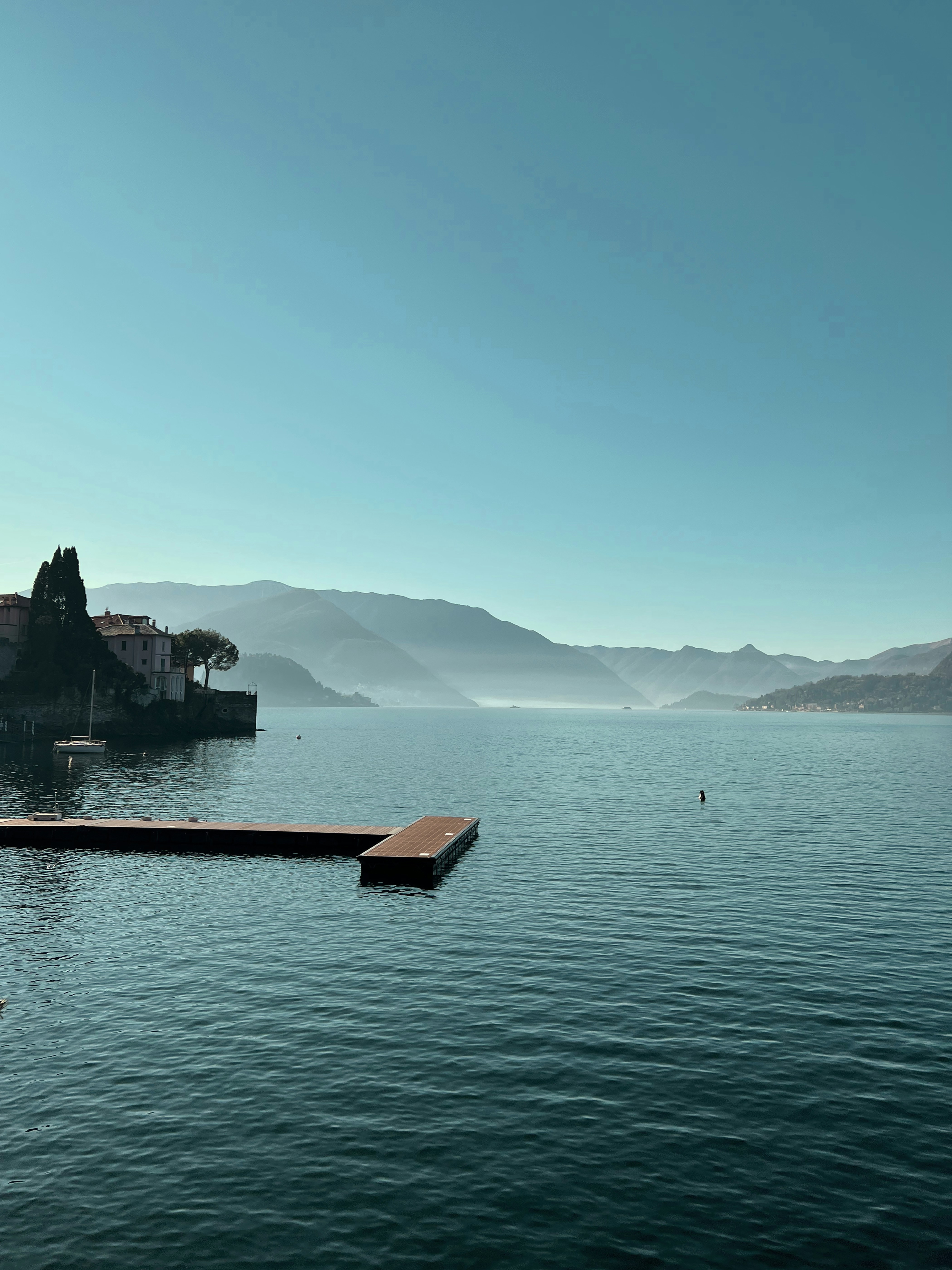 A body of water with a dock in the middle of it photo – Free Lake como ...