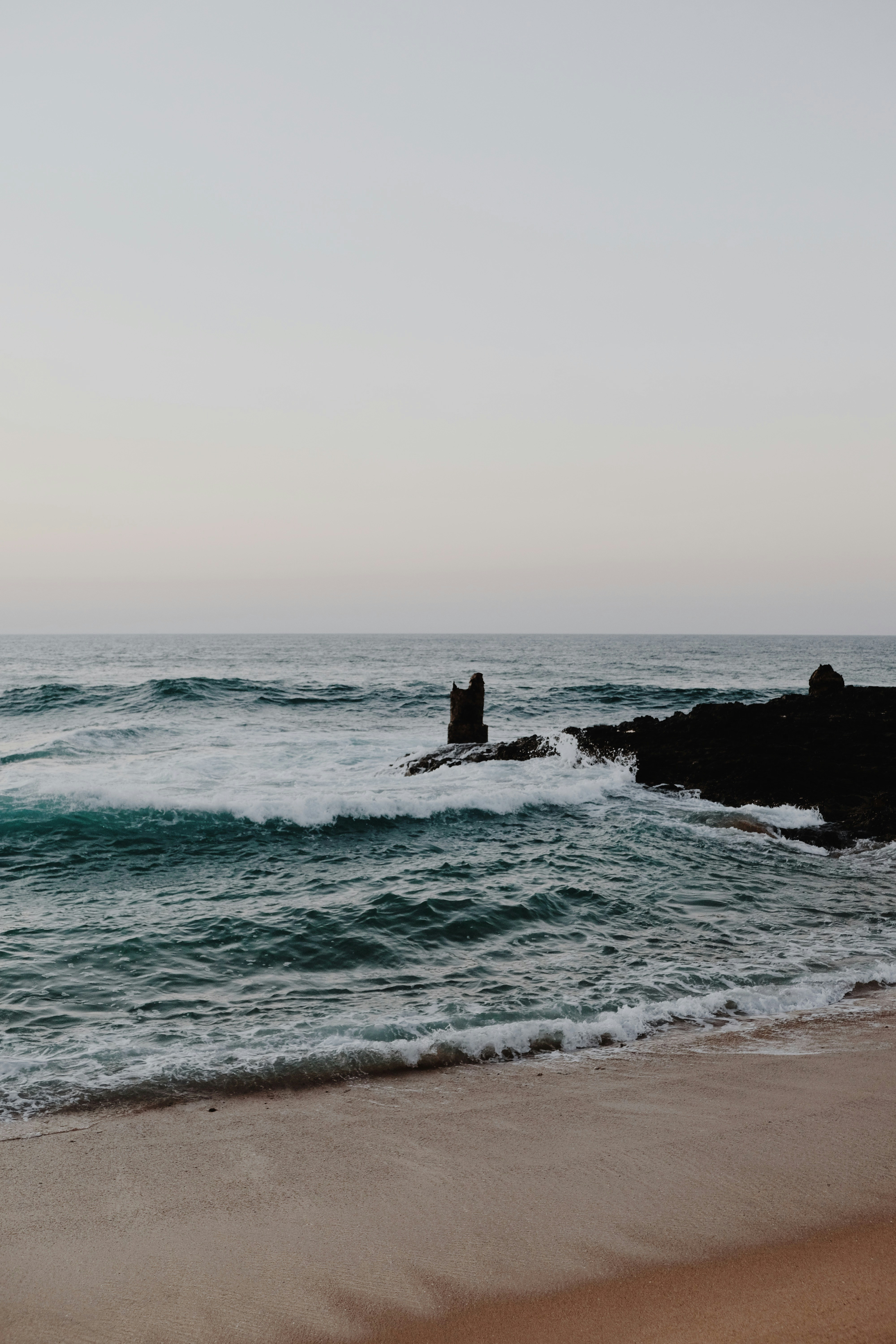 a couple of people sitting on top of a rock near the ocean