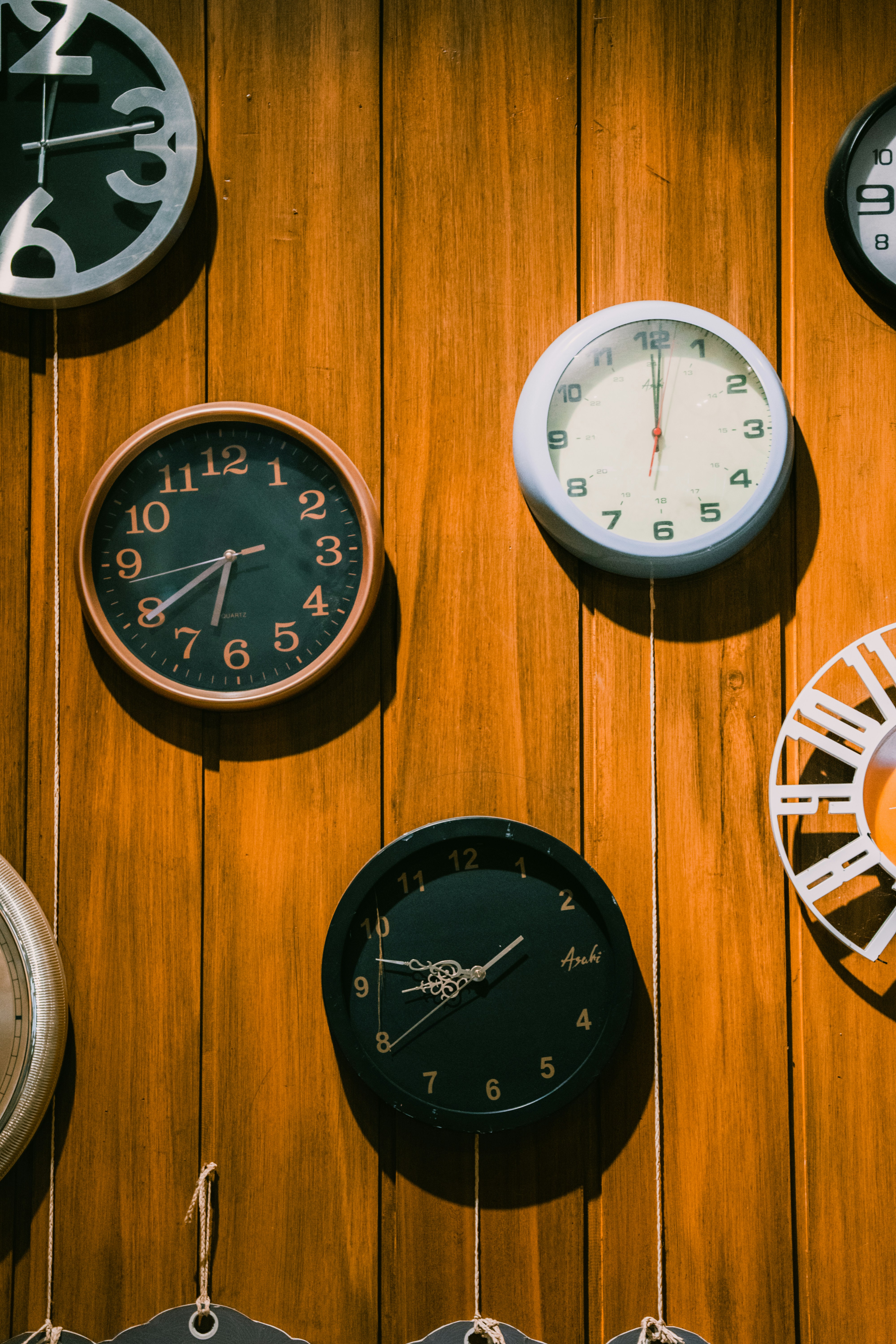 A group of clocks hanging on a wooden wall photo – Free Analog clock ...