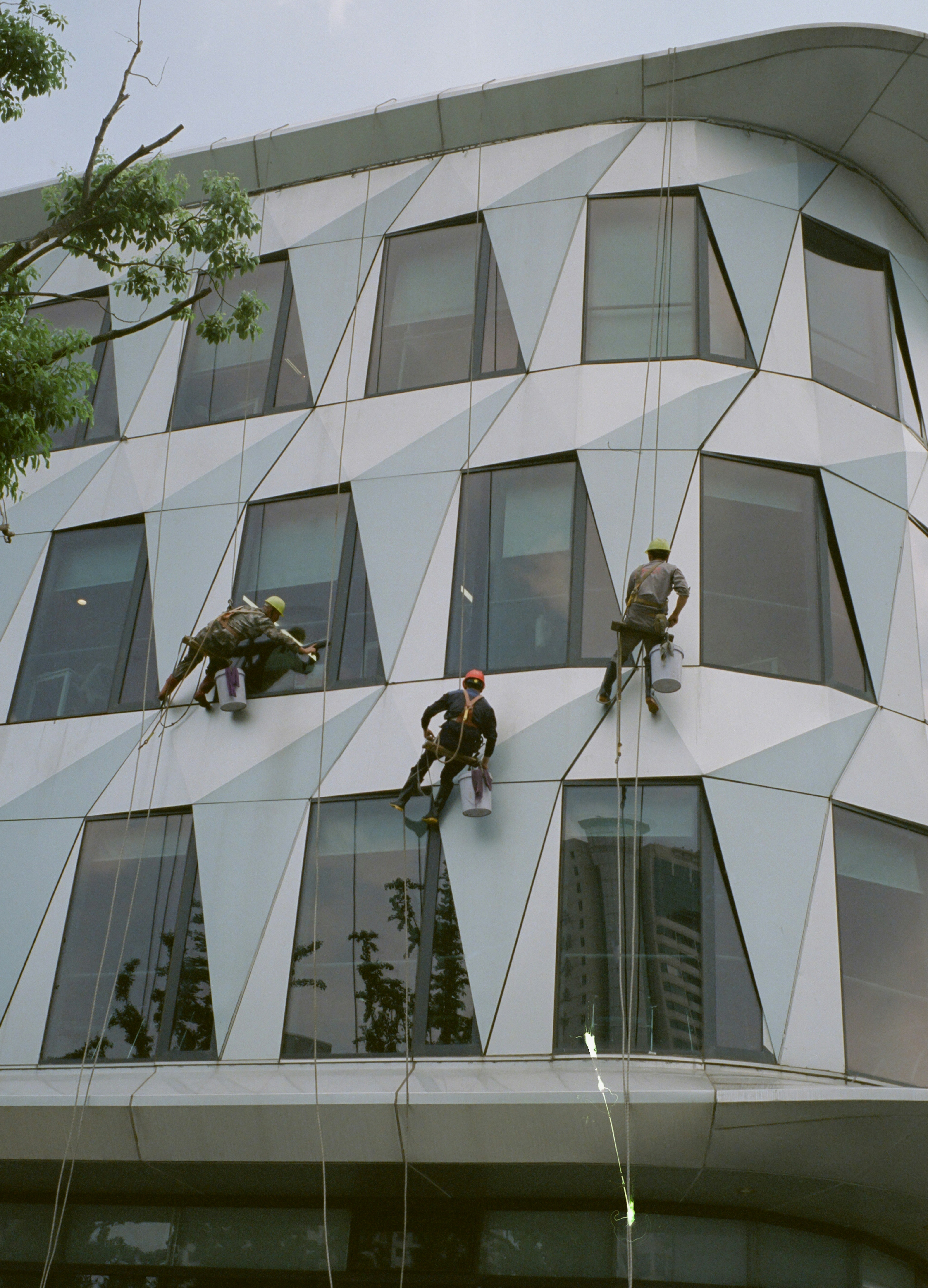 Climbers Adhering to a Faceted Facade under a Blue Sky