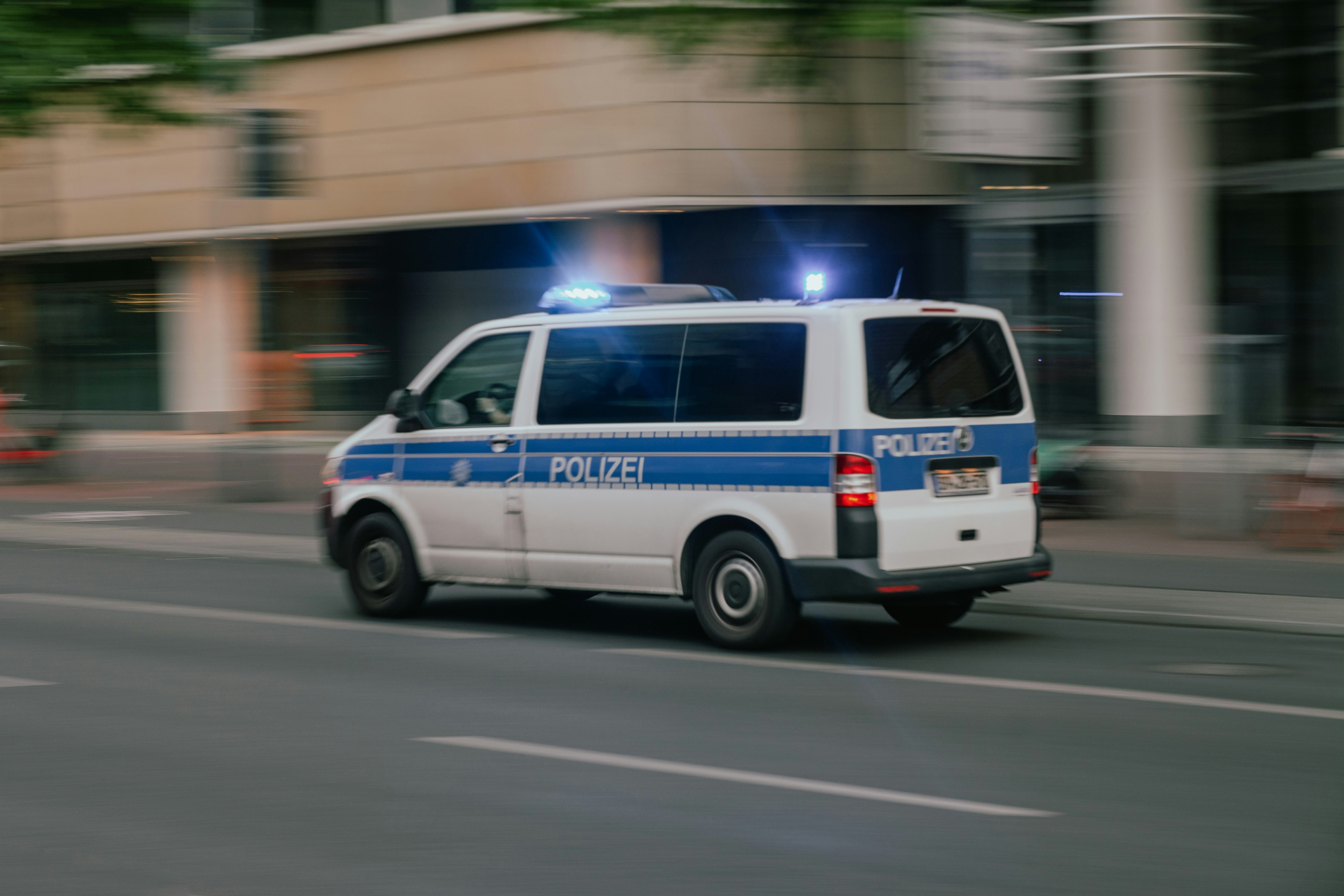 A police van with flashing lights navigates through a bustling city street, capturing the urgency of law enforcement in action.