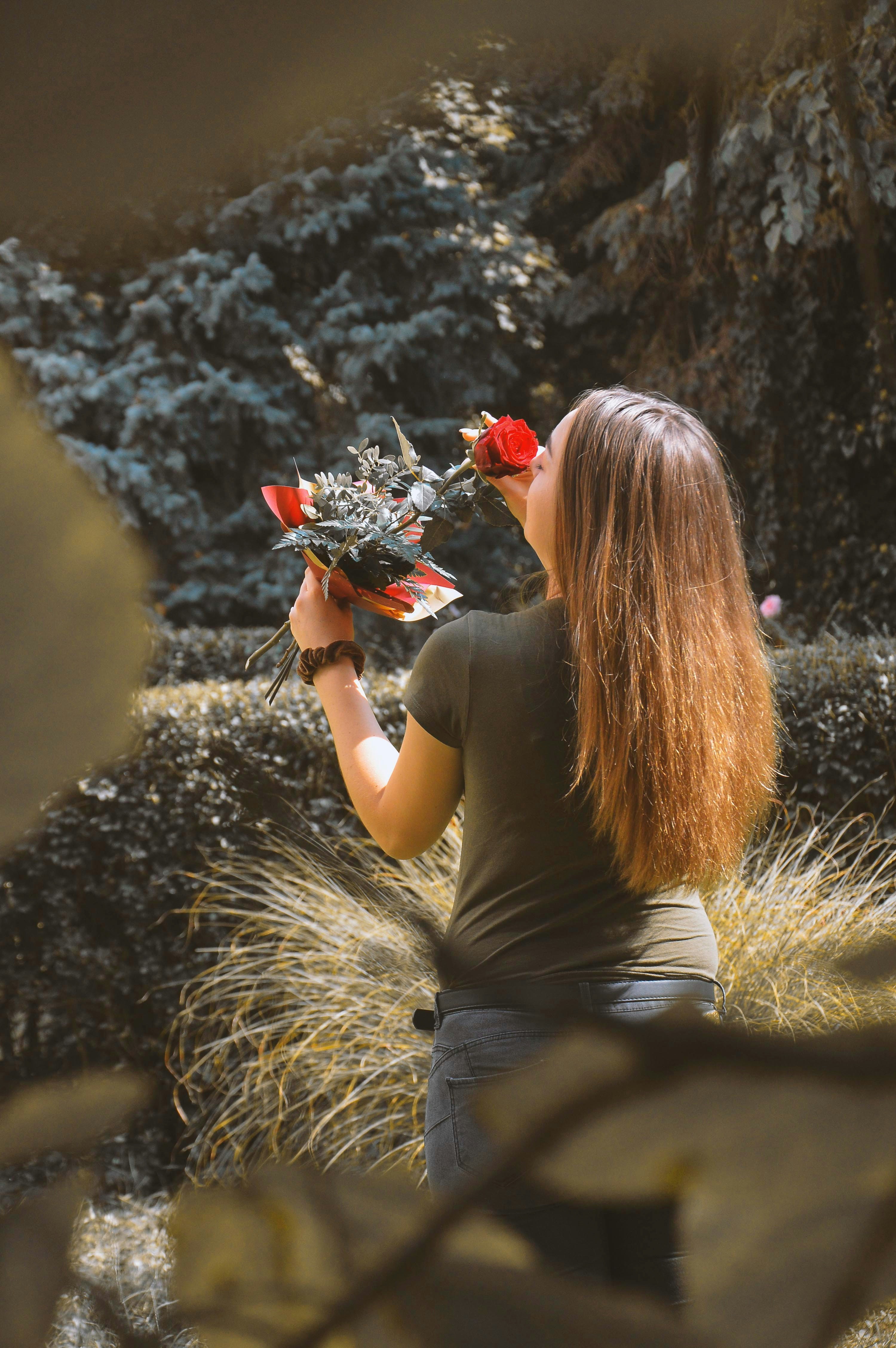 Une femme aux longs cheveux roux tenant une fleur photo – Image ...