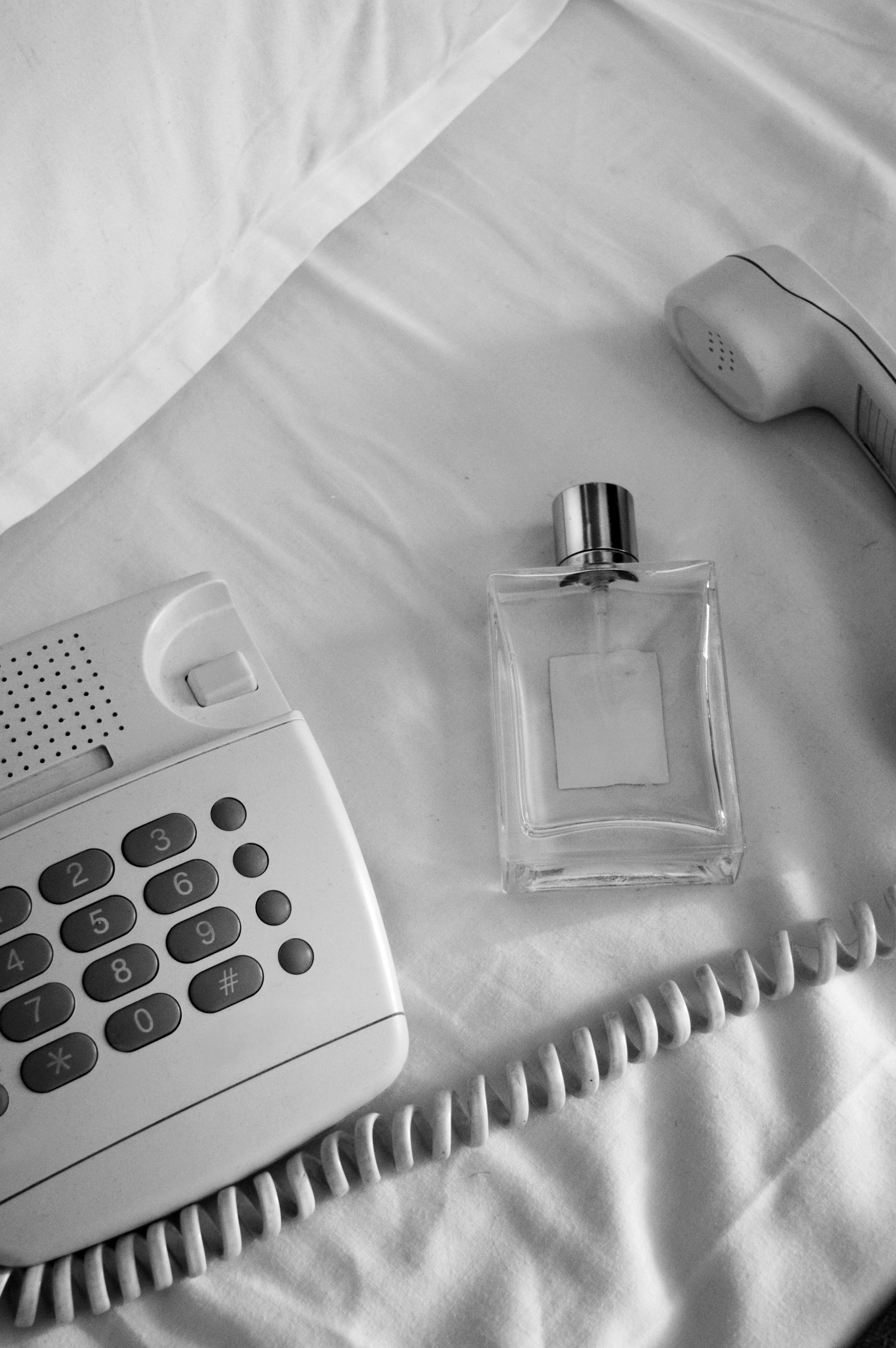 A telephone, a bottle of perfume and a phone on a bed photo – Free ...
