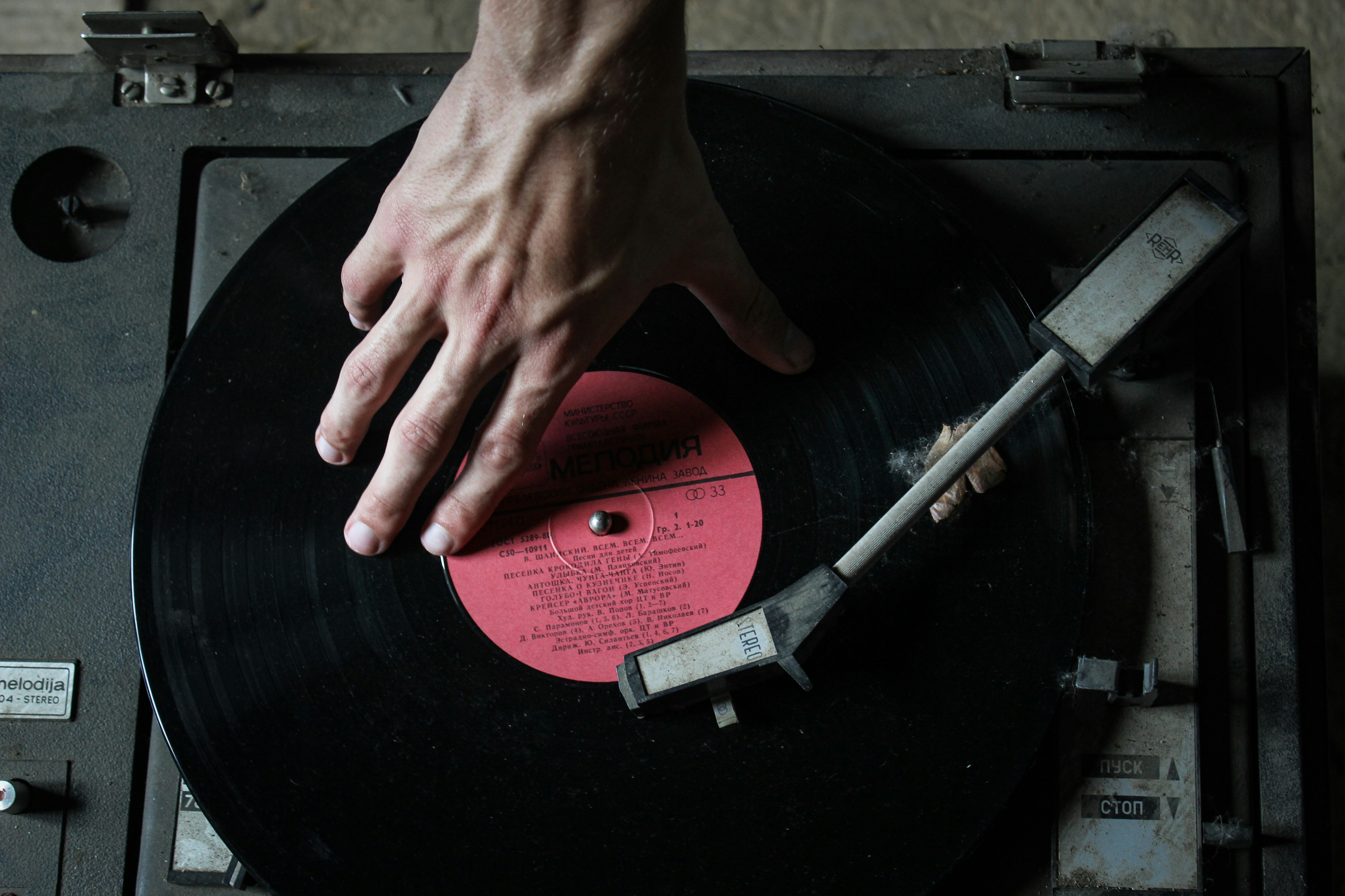A hand gently rests on a spinning vinyl record, highlighting the tactile connection between music and memory. The turntable's vintage design adds a nostalgic touch.