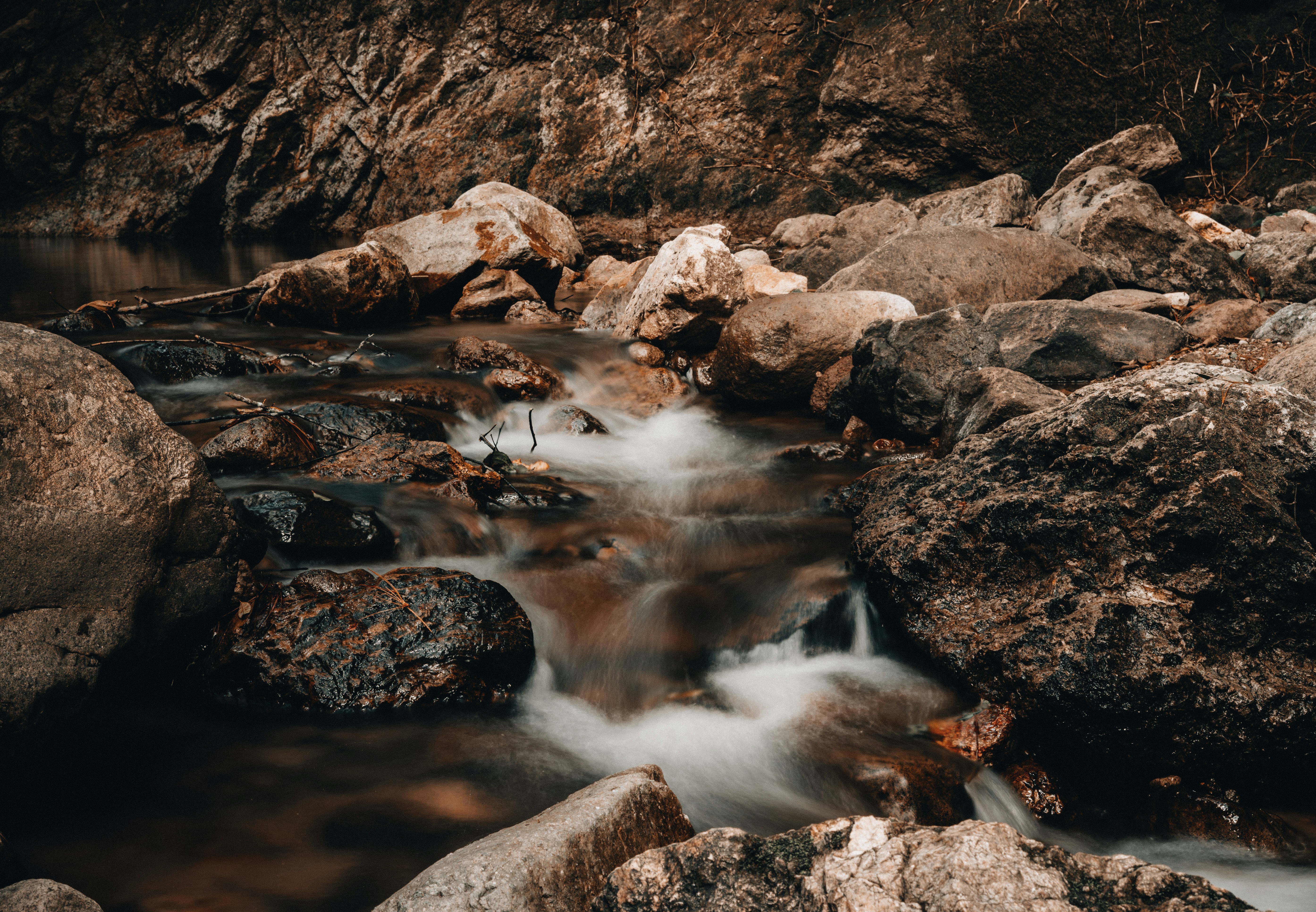 A small stream of water running between rocks photo – Free Water Image ...