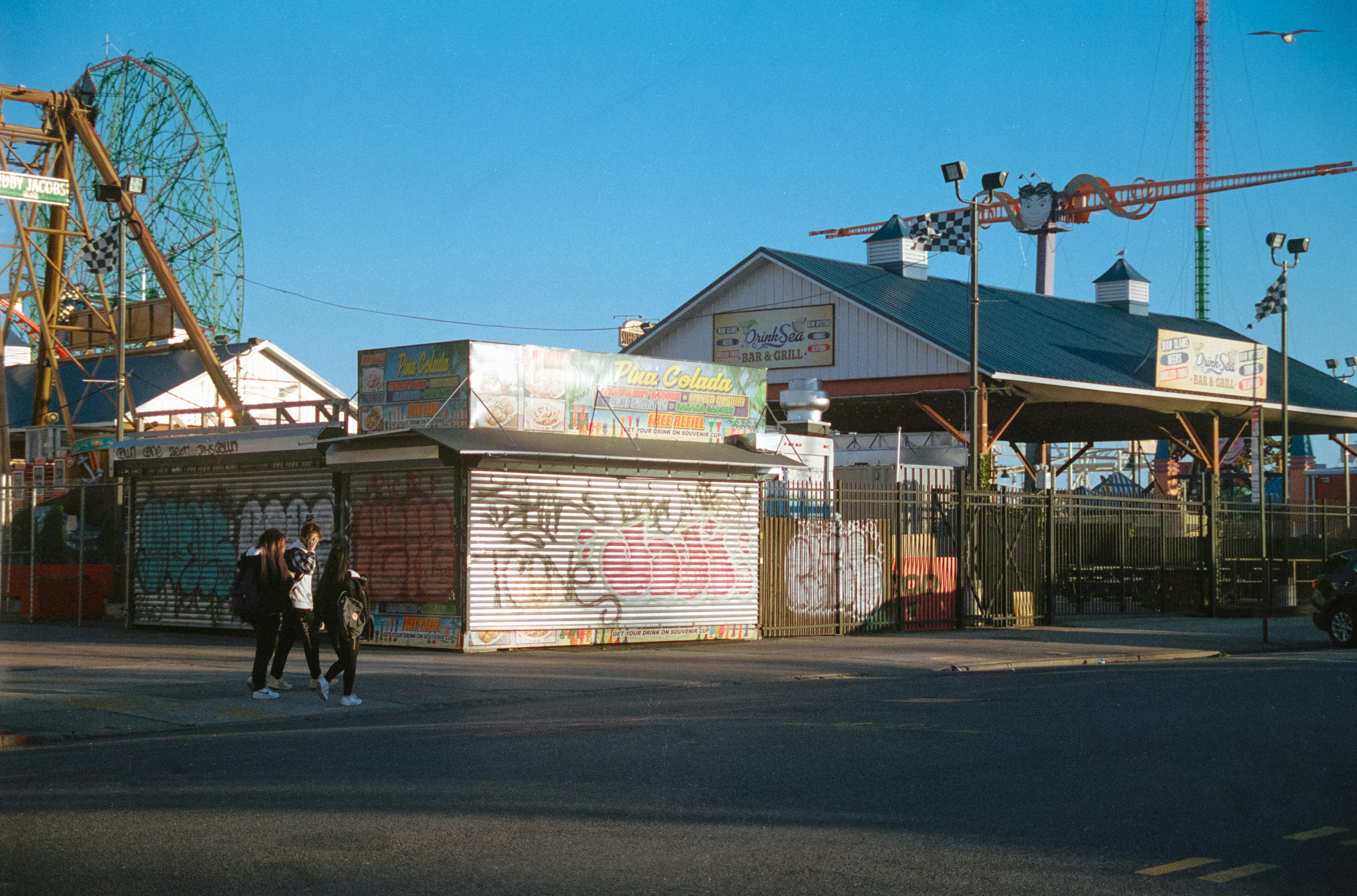 Graffiti-Kissed Kiosk at the Edge of a Sunlit Amusement Row