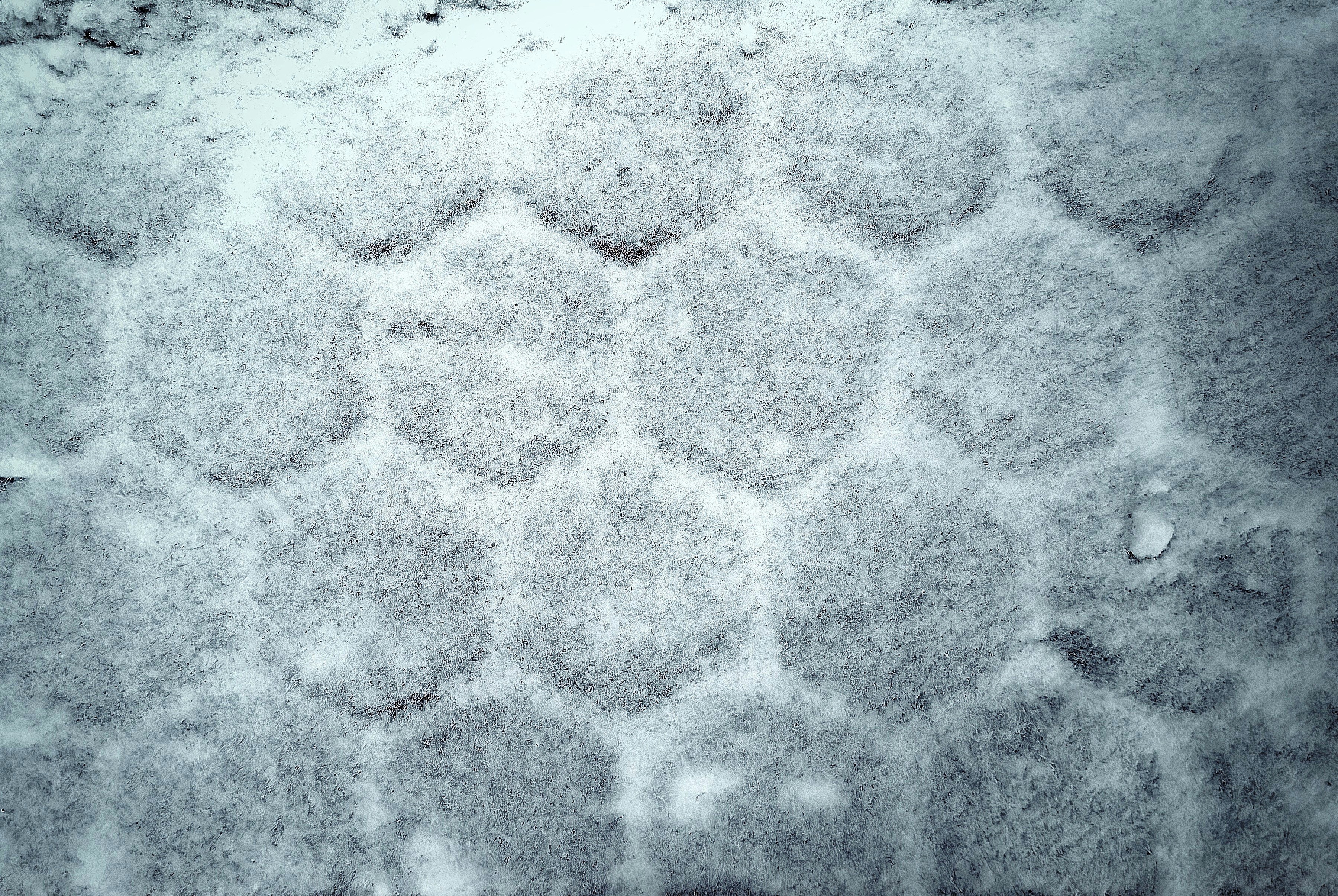Intricate hexagonal patterns formed by snowflakes blanketing the ground, showcasing nature's design. The scene captures the delicate beauty of winter's touch.