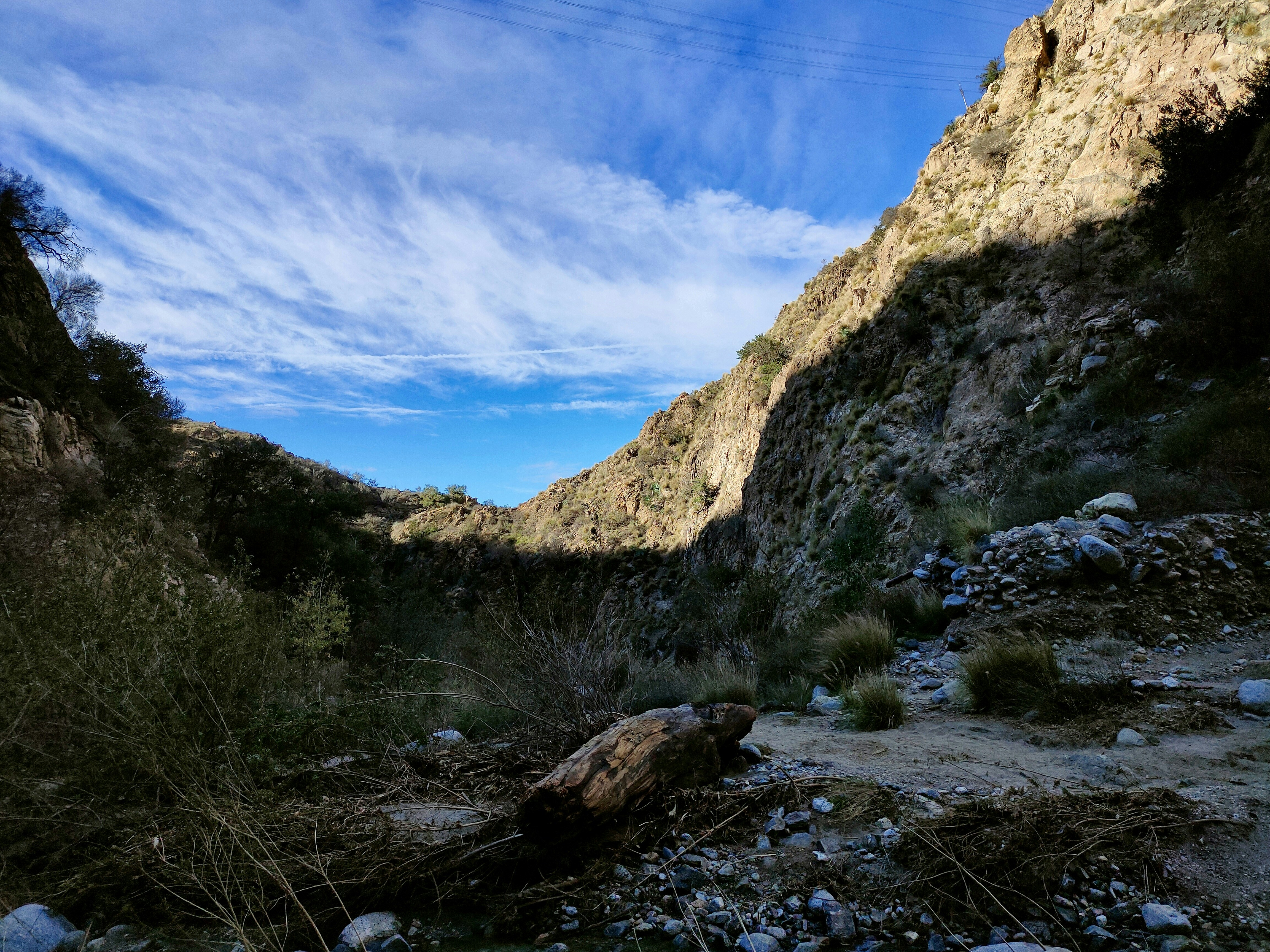 Rocky canyon path under a vibrant blue sky with scattered clouds.