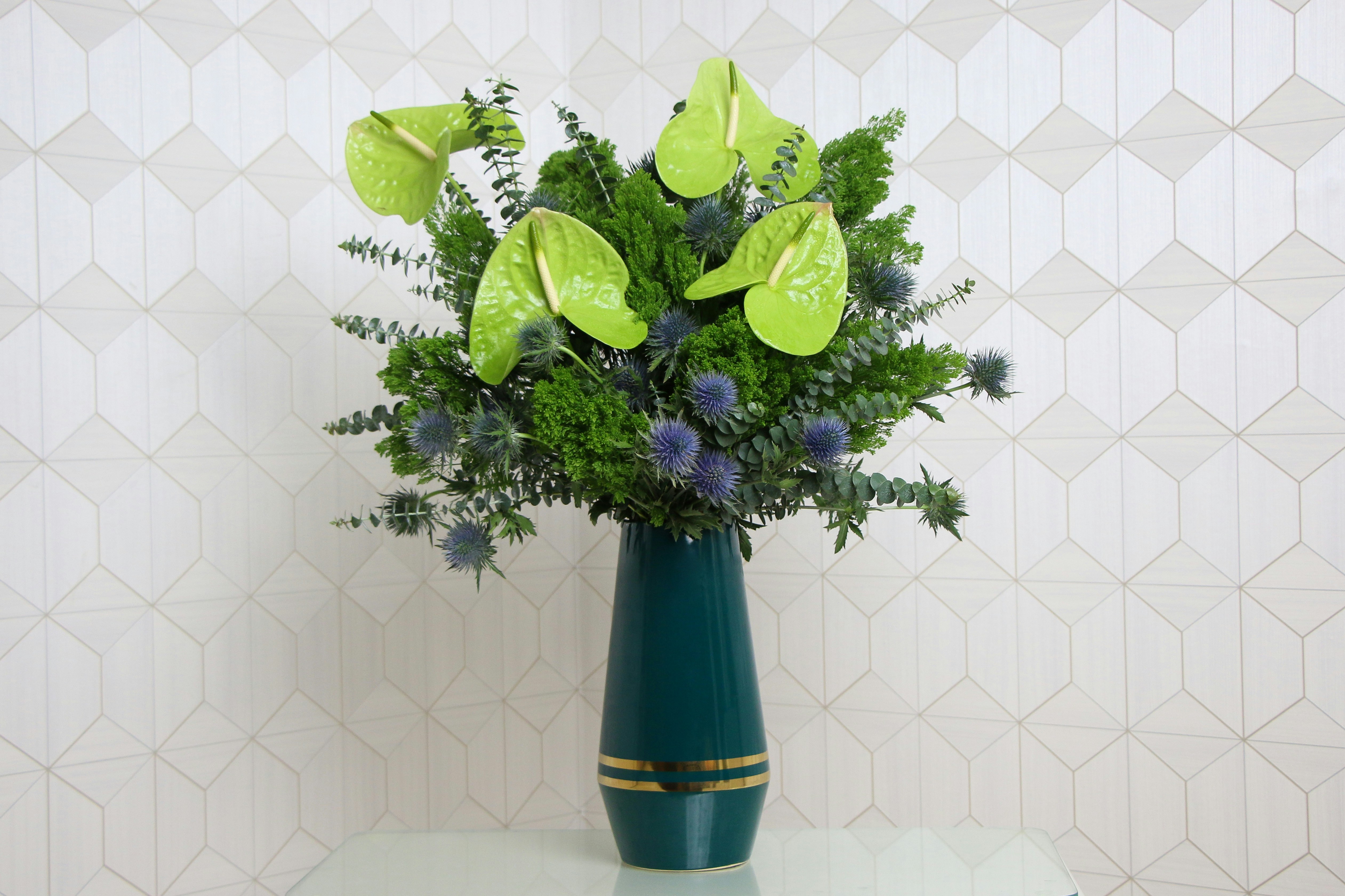 Verdant Centerpiece: Teal Vase Amid Lime Foliage and Violet Accents