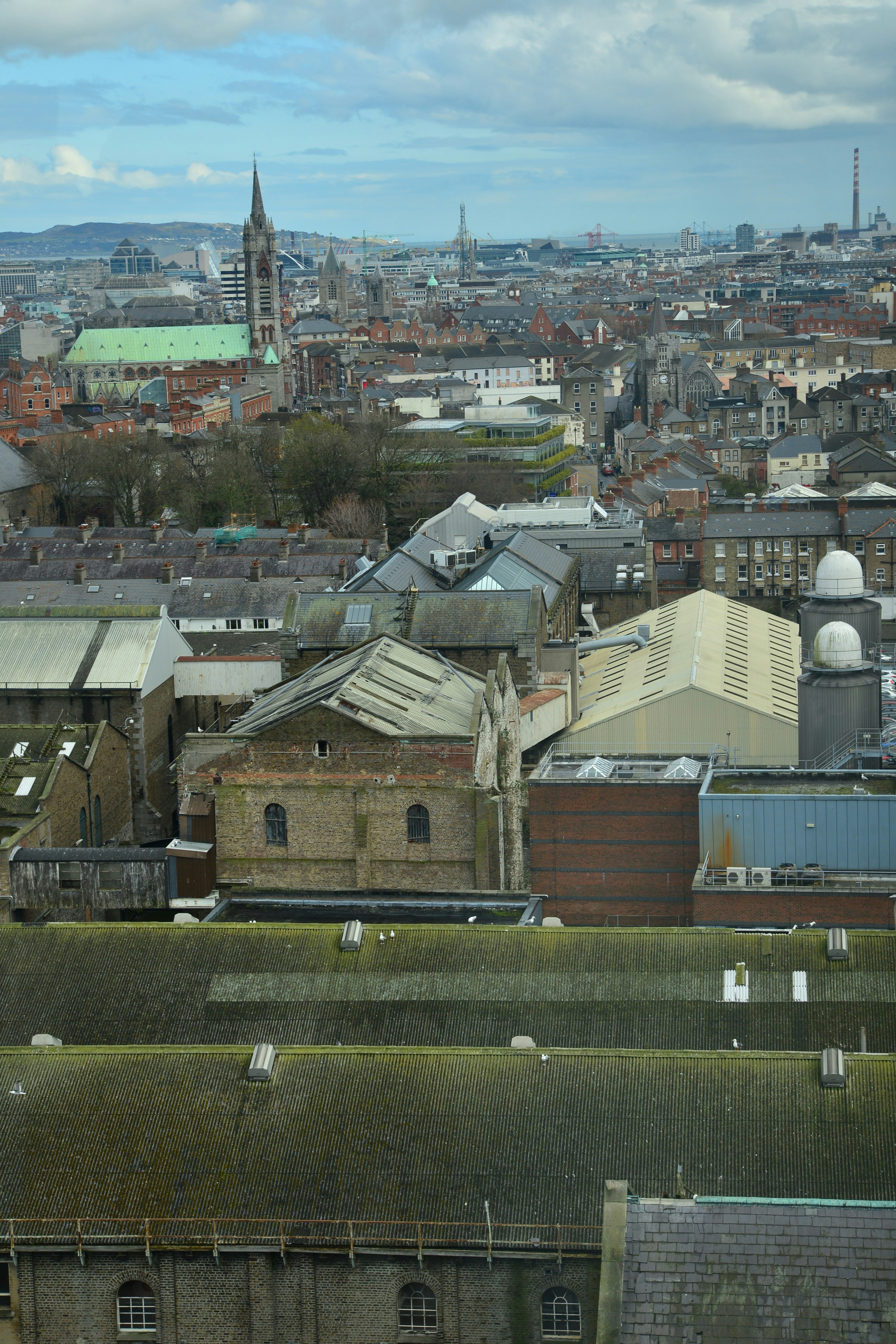 A panoramic view of a bustling cityscape, showcasing a mix of historic and modern architecture against a cloudy sky.