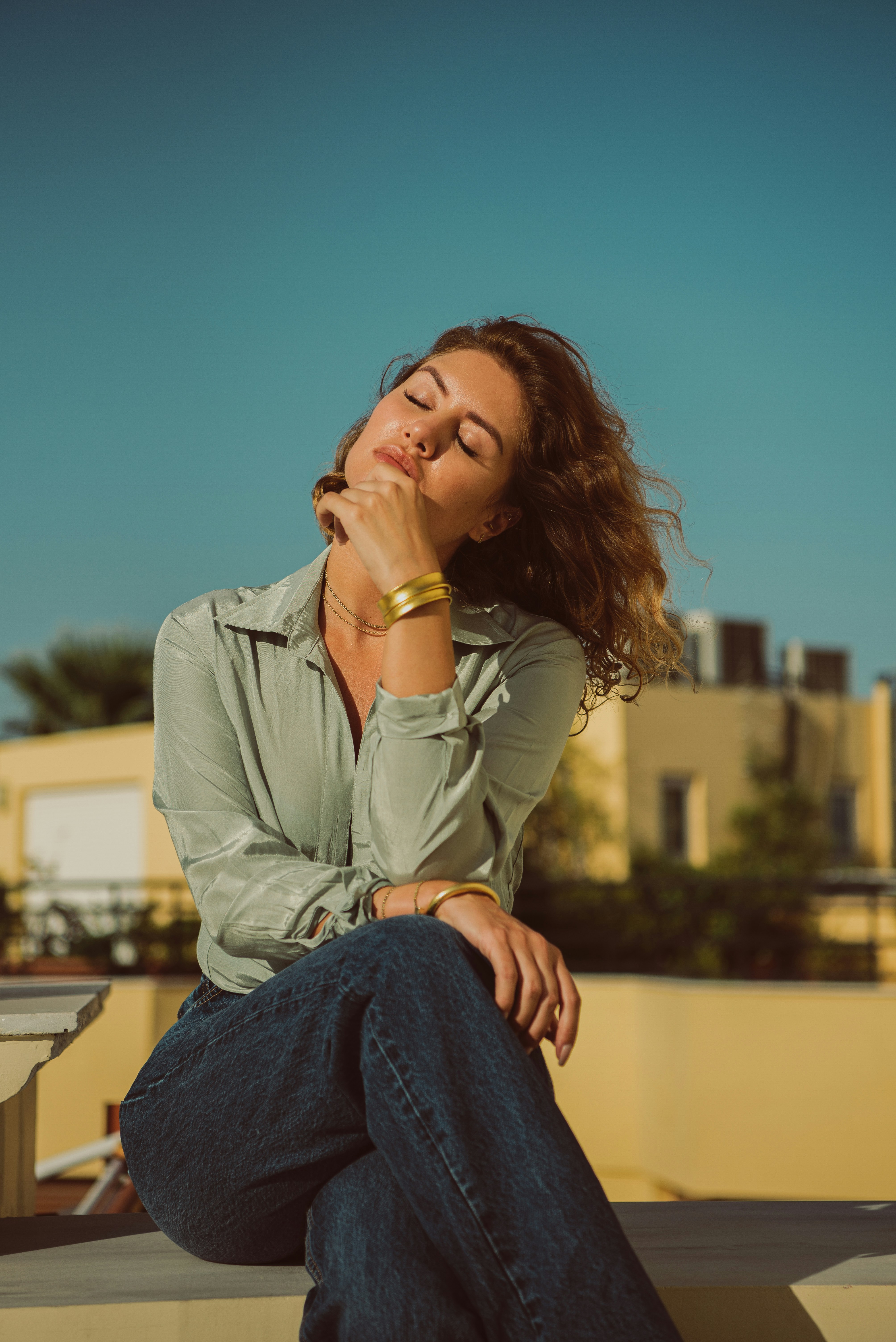 A woman sitting on a ledge with her eyes closed photo – Free Athens ...