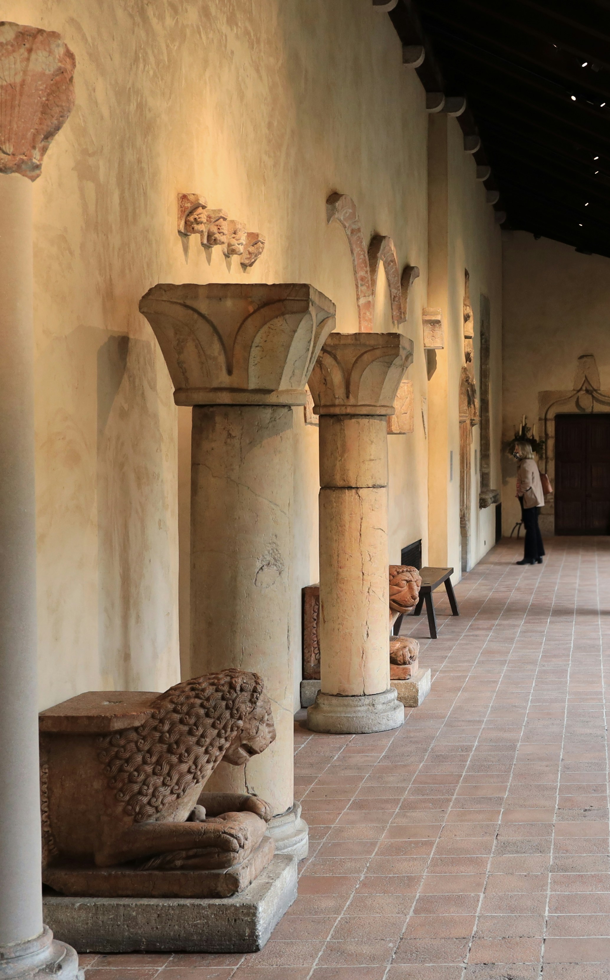 A person walking down a hallway between two stone pillars photo – Free ...