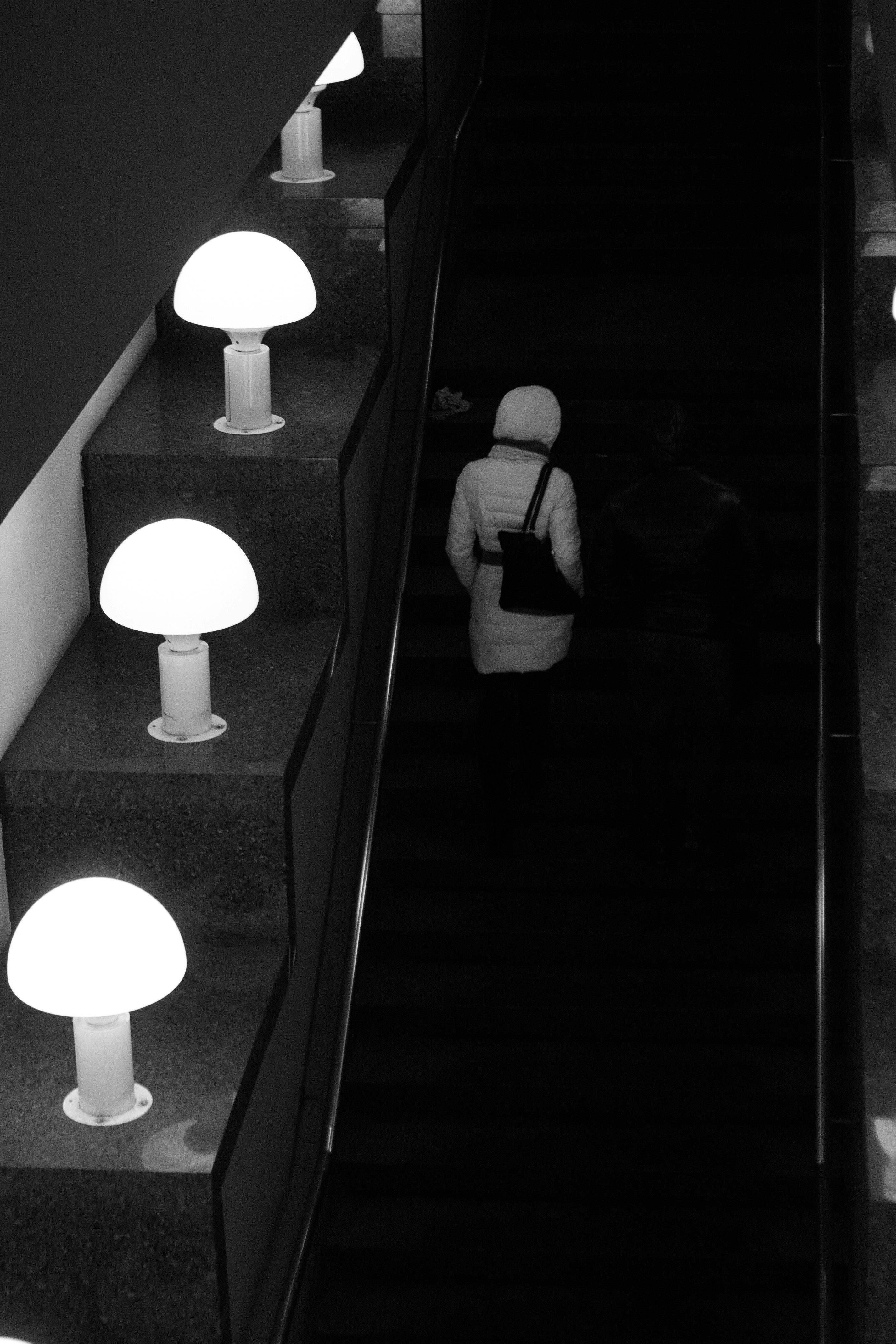 a black and white photo of a person walking down a flight of stairs