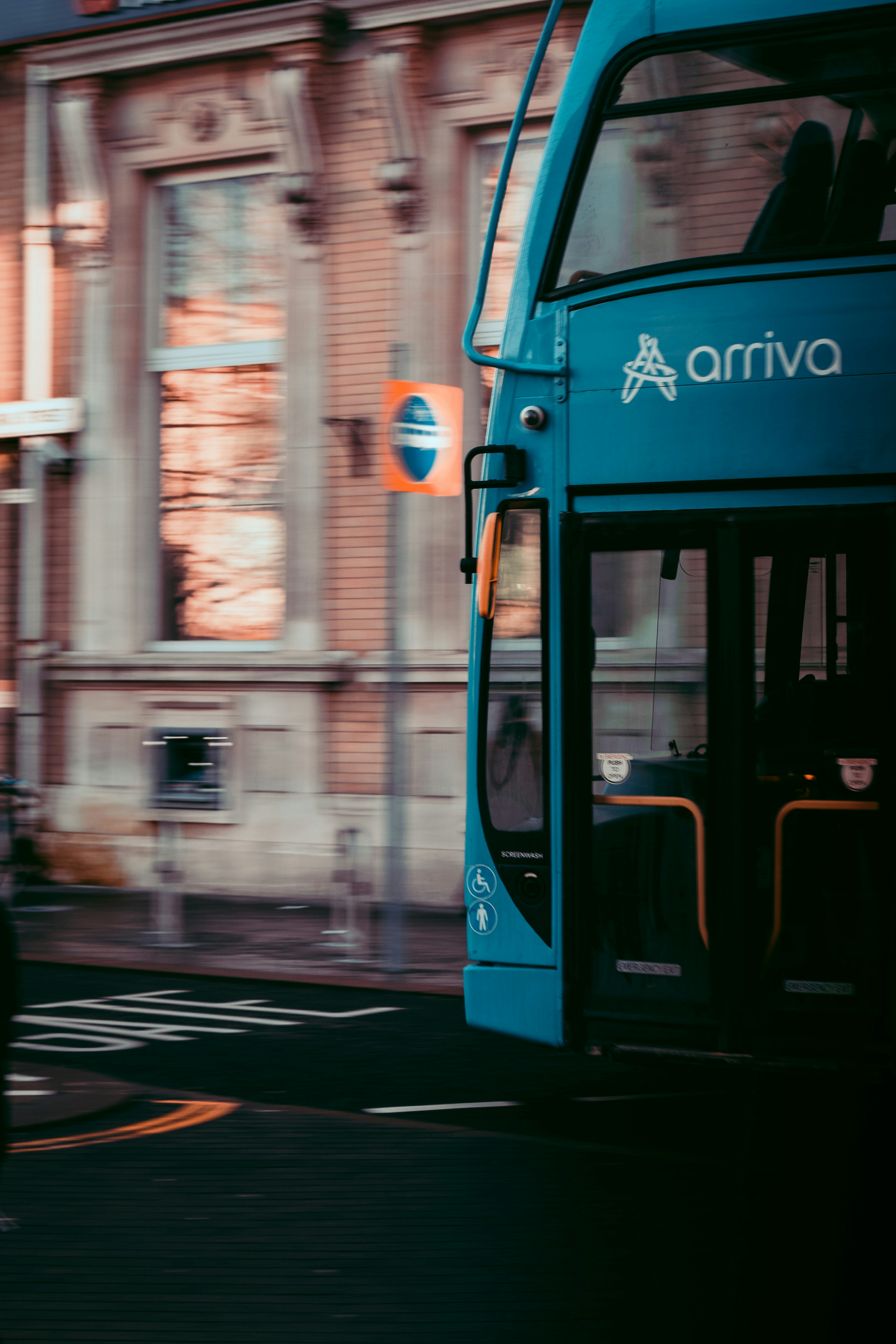 Blue double-decker bus passing by a historic building on a city street.