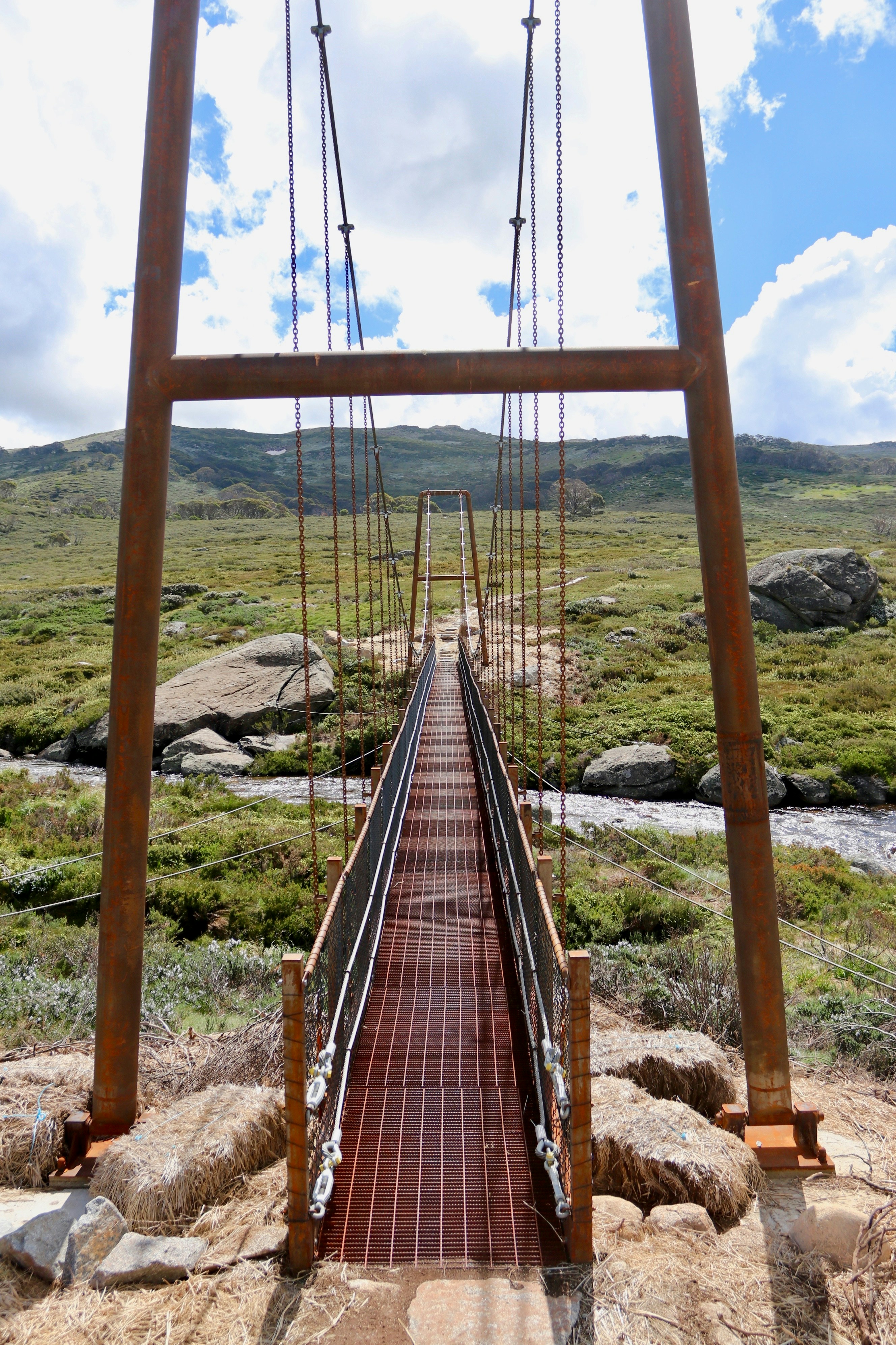 A wooden suspension bridge over a stream in the mountains photo – Free ...