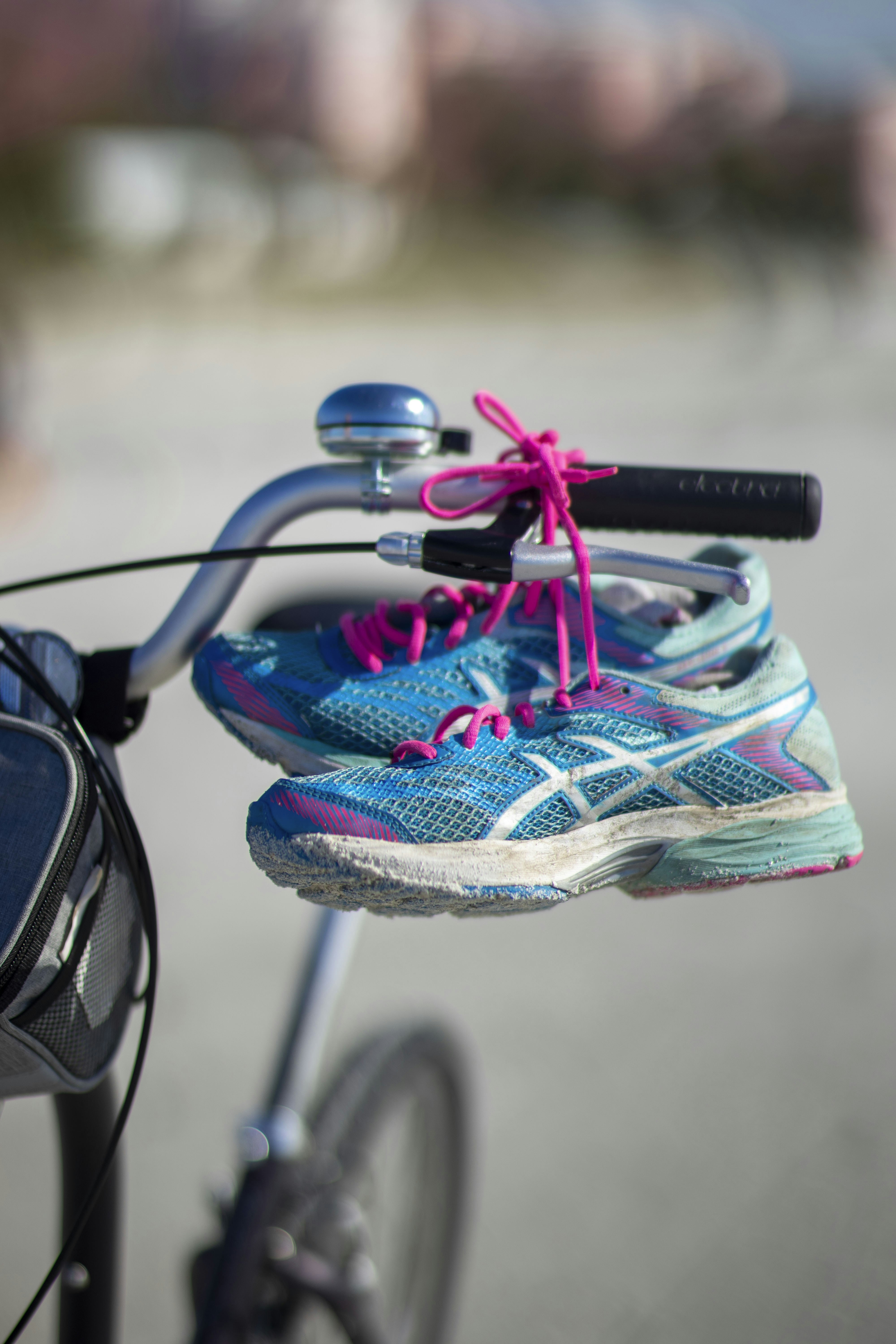 Vivid Teal Running Shoes Dangling Over a Bicycle Handlebar