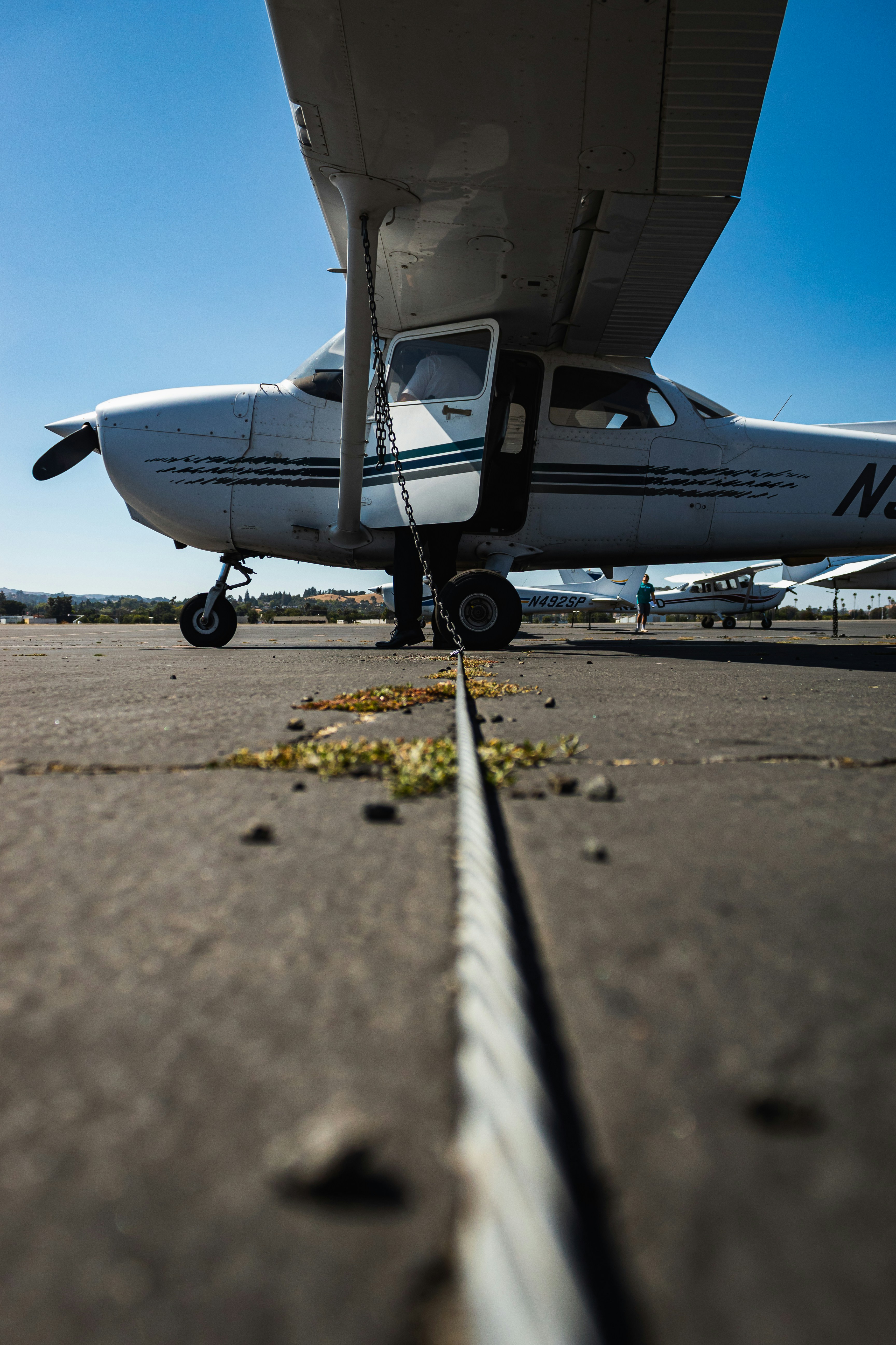 Under Tethered Light: A Low-Angle Portrait of a Small Plane on a Sunlit Apron