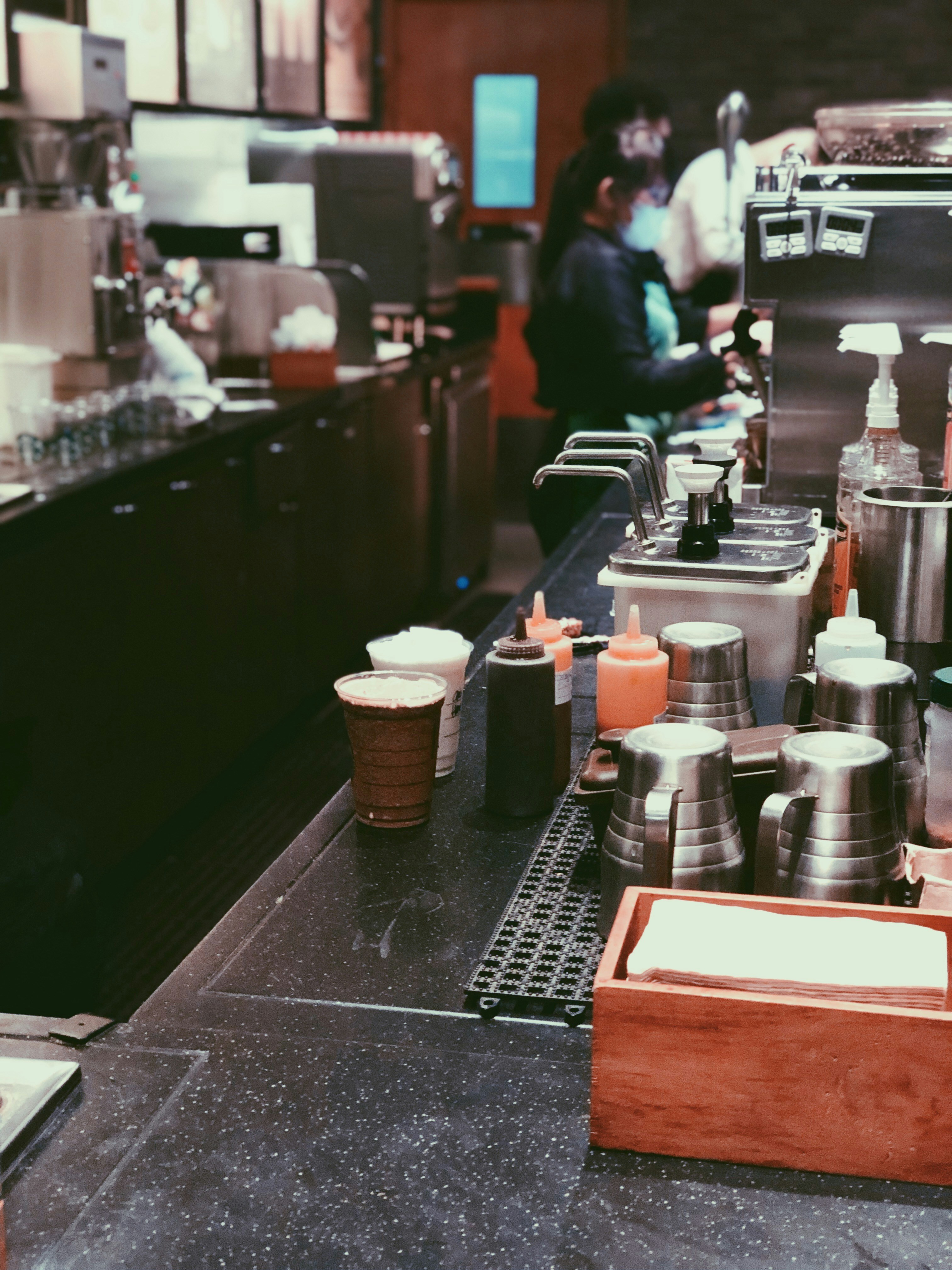 Baristas expertly preparing beverages at a coffee shop, showcasing a variety of ingredients and tools. The bustling environment captures the essence of coffee culture.
