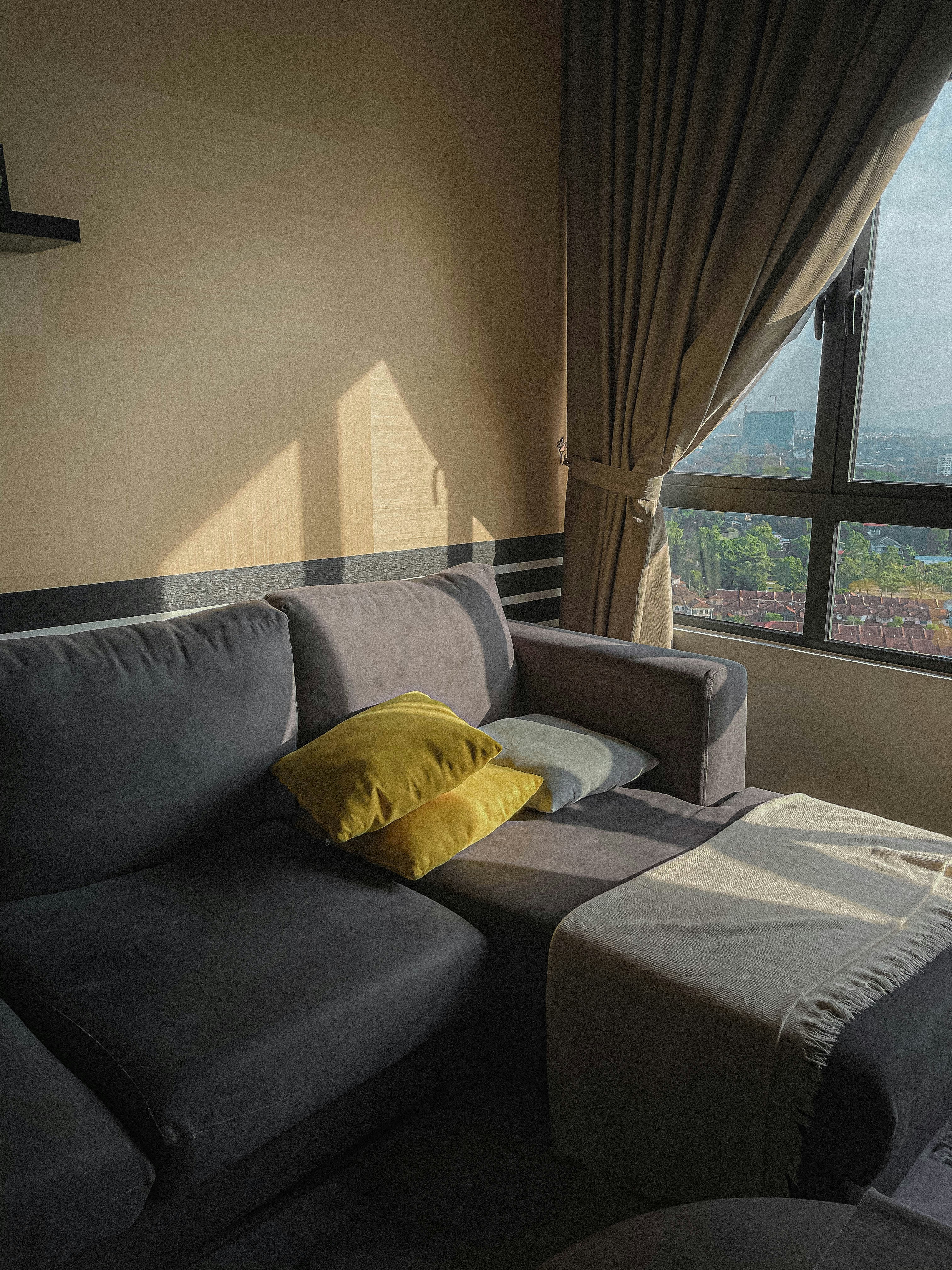 Sunlit Nook: Cozy Gray Sofa and Bold Yellow Cushions by the Window