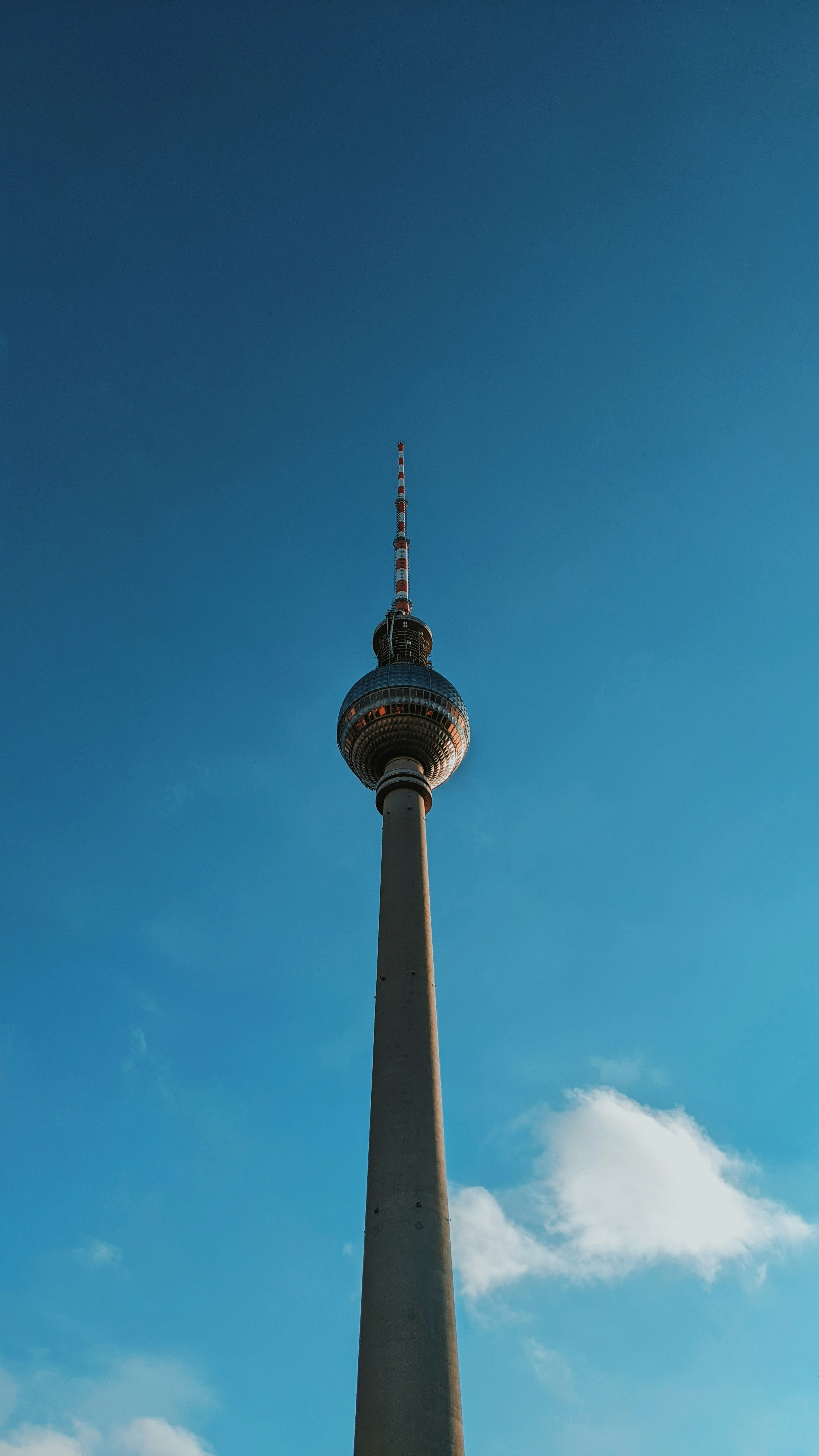The Berlin TV Tower rises majestically against a clear blue sky, showcasing its distinctive design and structure.