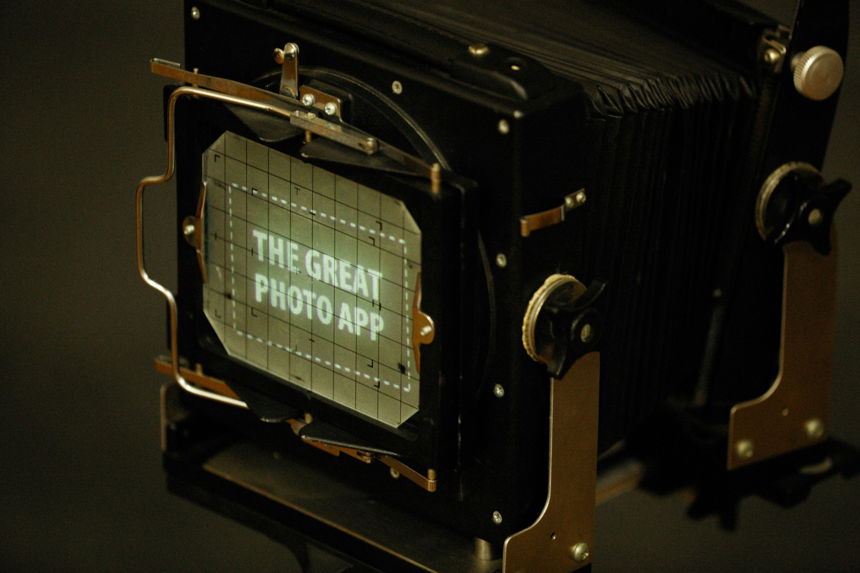 An antique camera displaying a screen with 'THE GREAT PHOTO APP' illuminated, showcasing the blend of classic design and modern technology.