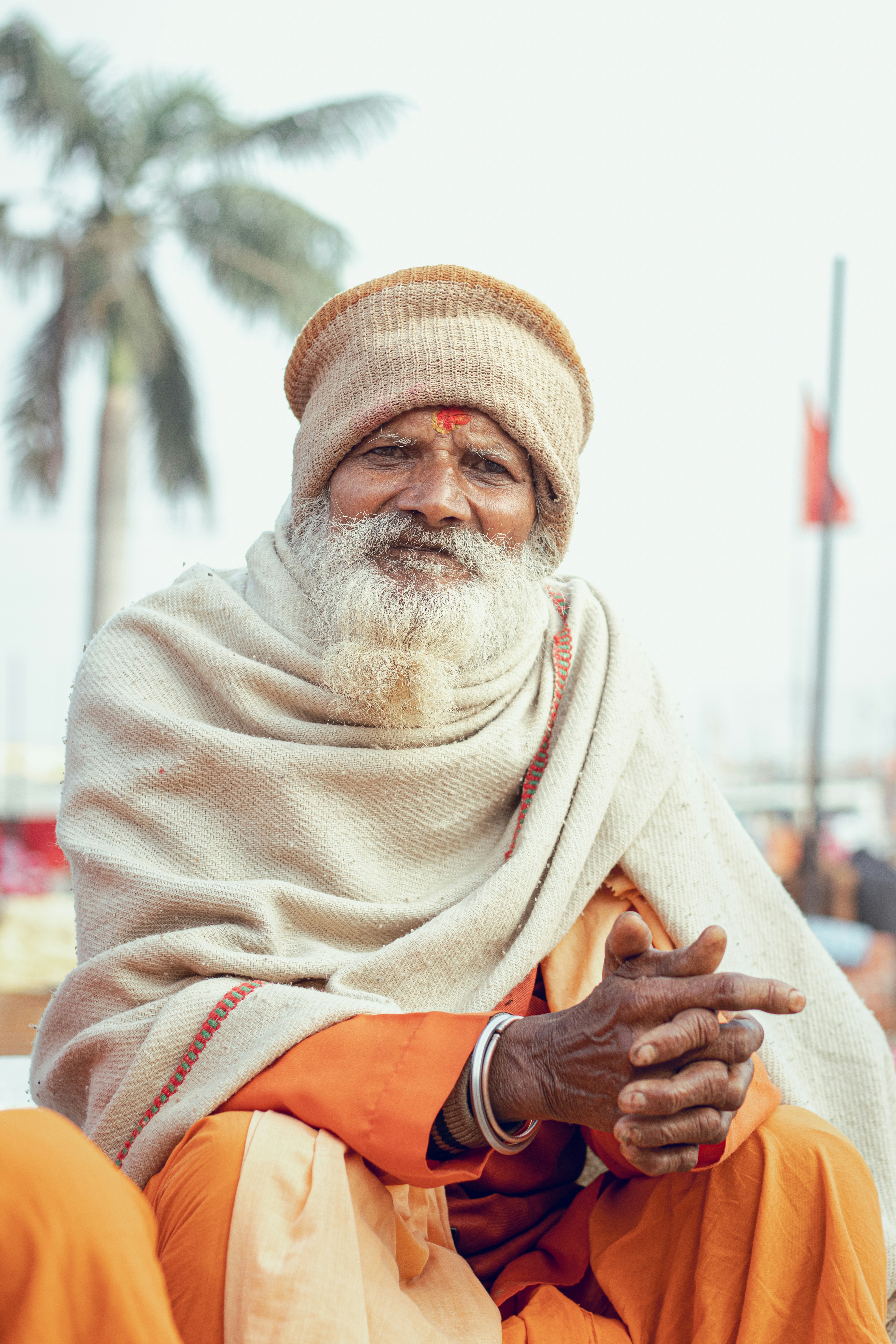 Seaside Sage: A Weathered Monk Wrapped in White by the Boardwalk