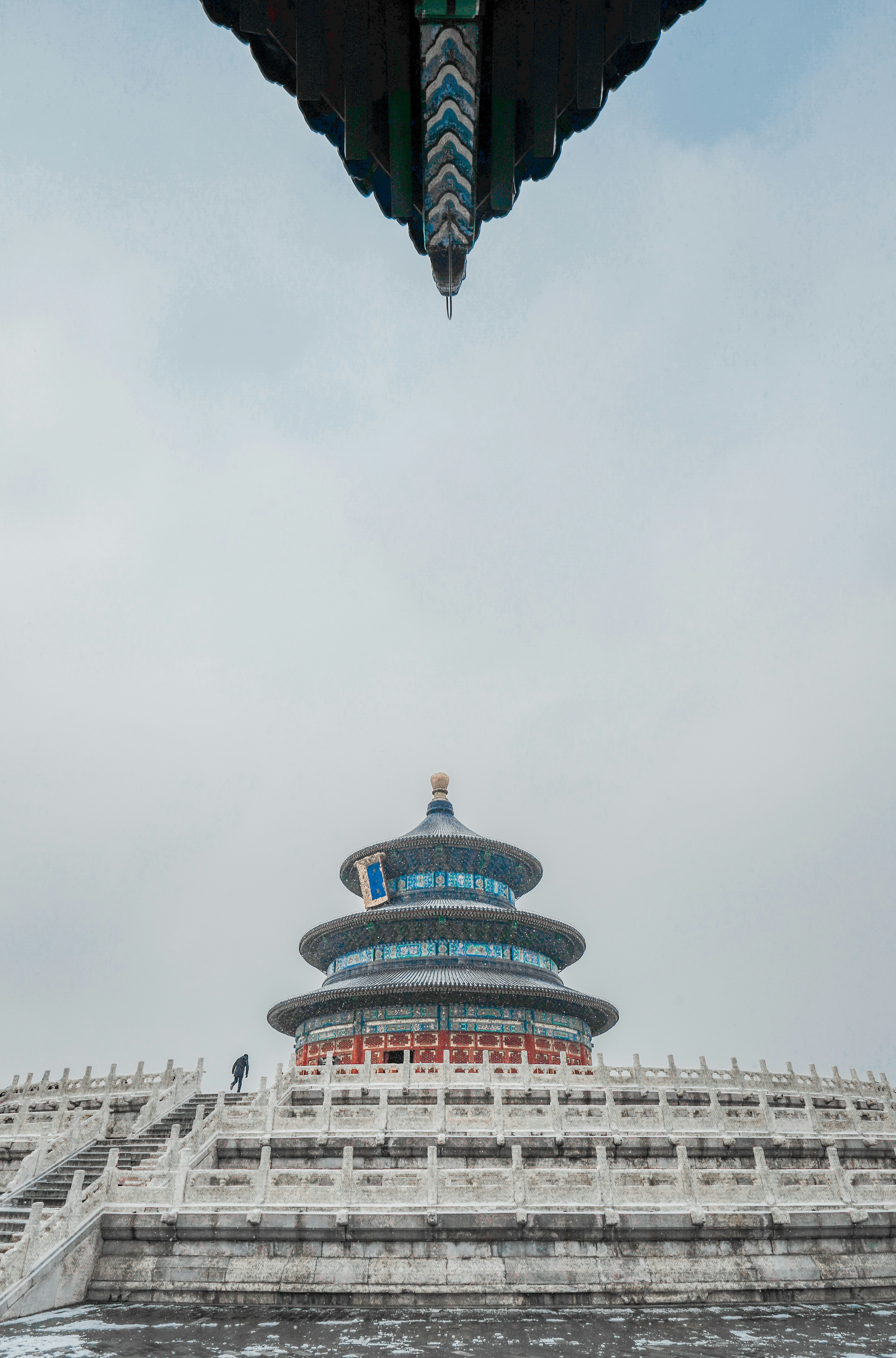 Intricate details of the Temple of Heaven captured from a low angle, emphasizing its majestic structure against a cloudy sky.