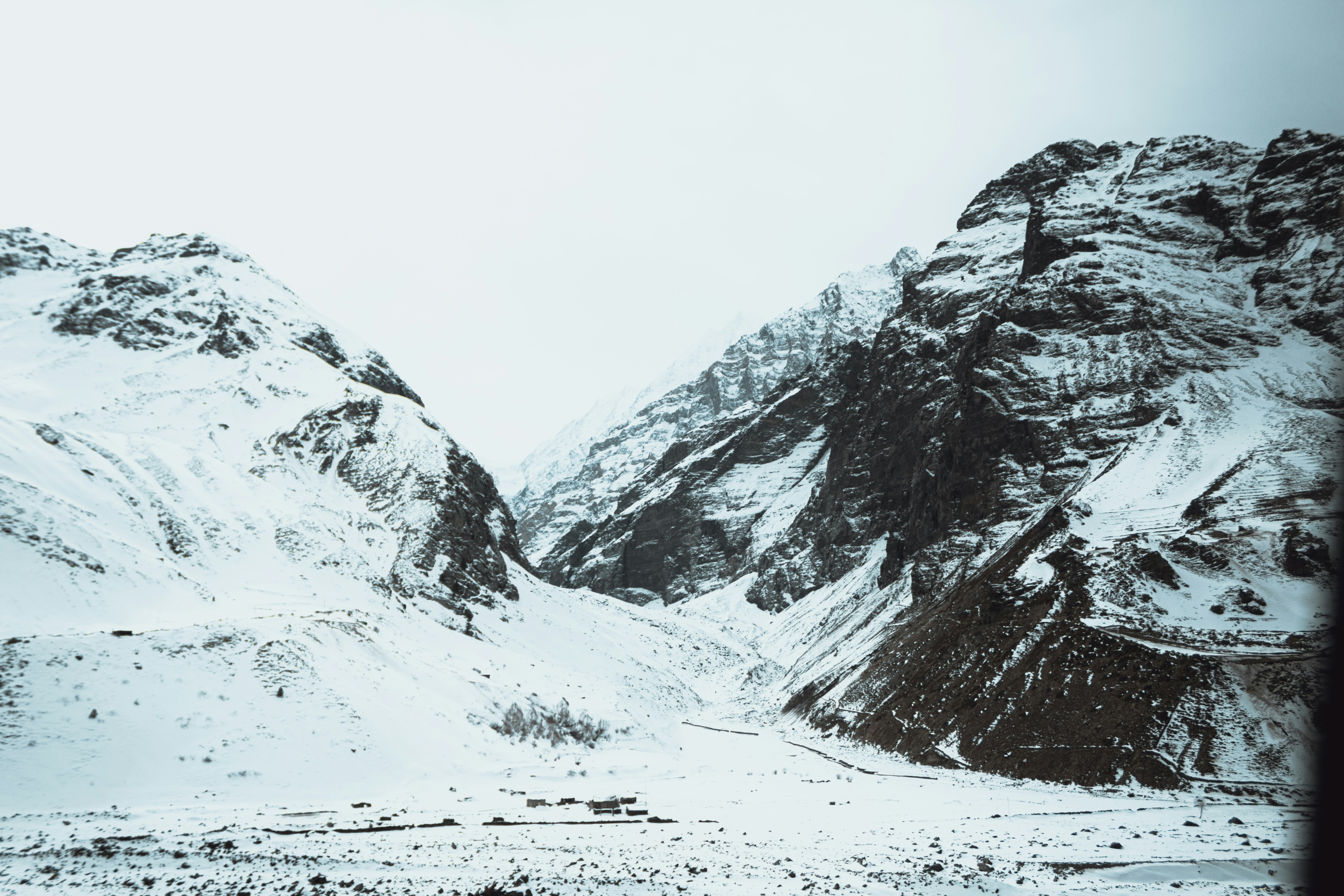 Snow-covered mountains create a serene and rugged landscape under an overcast sky.