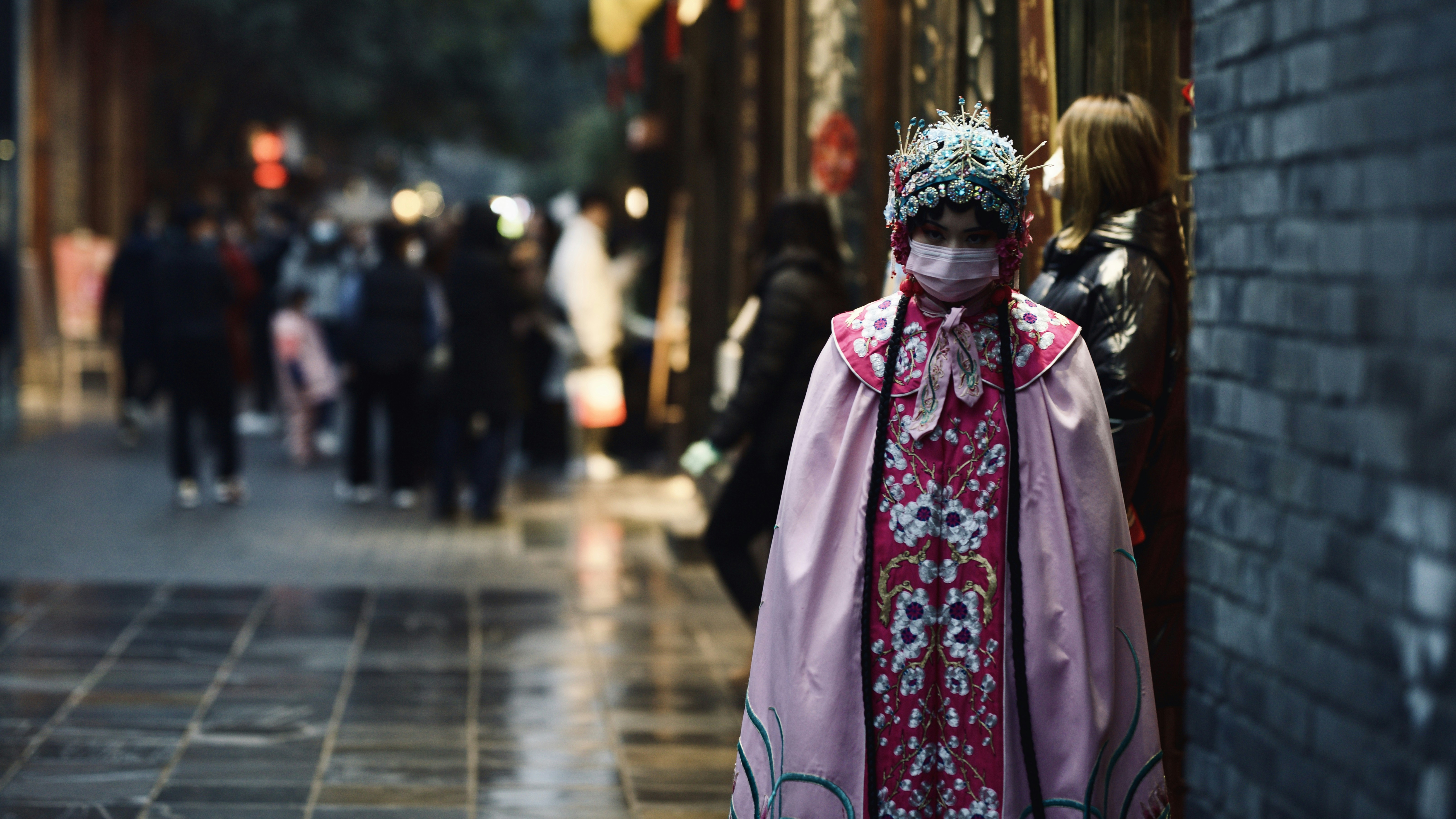 a woman wearing a face mask and a pink coat