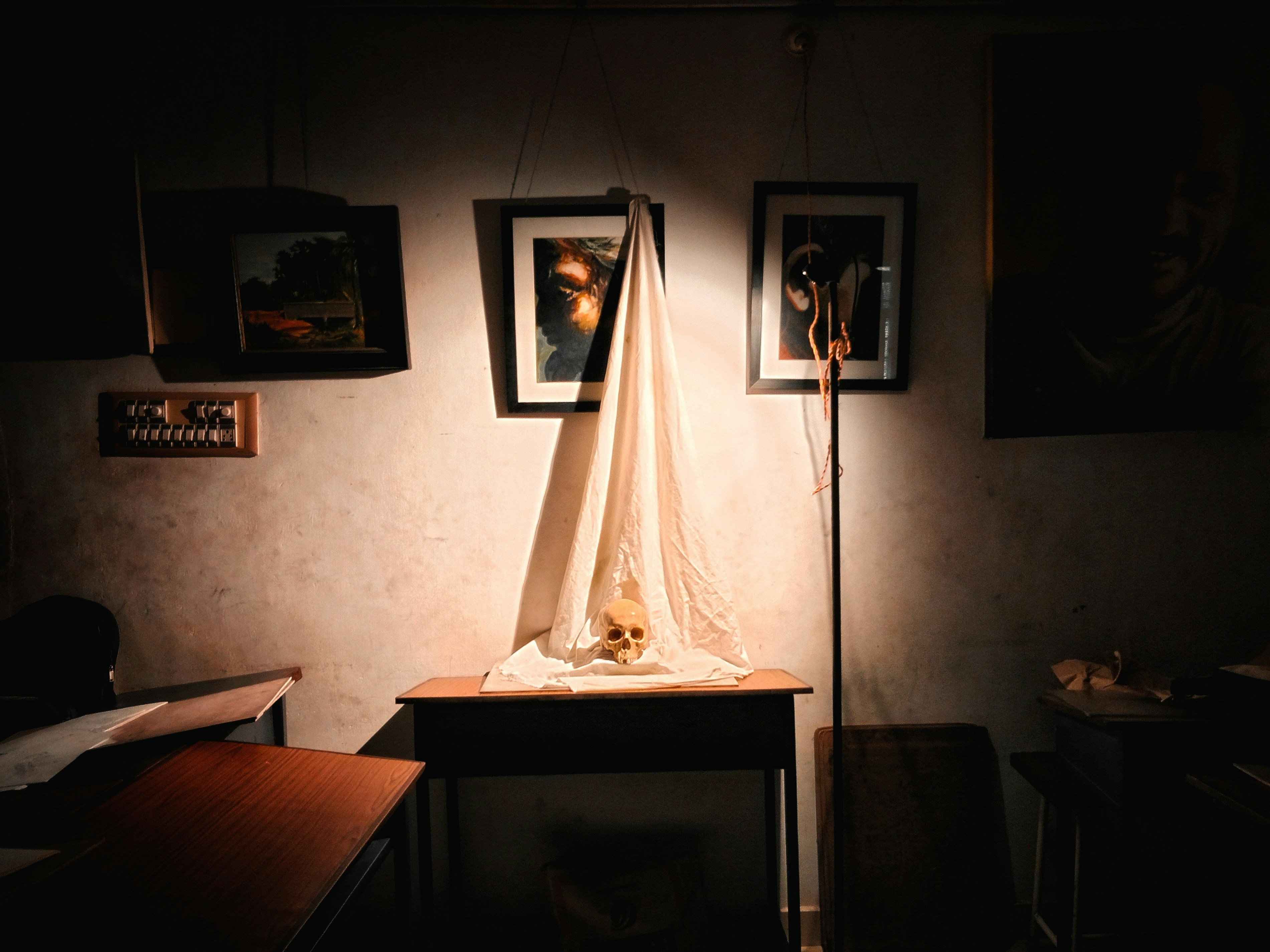a dark room with a lamp and pictures on the wall