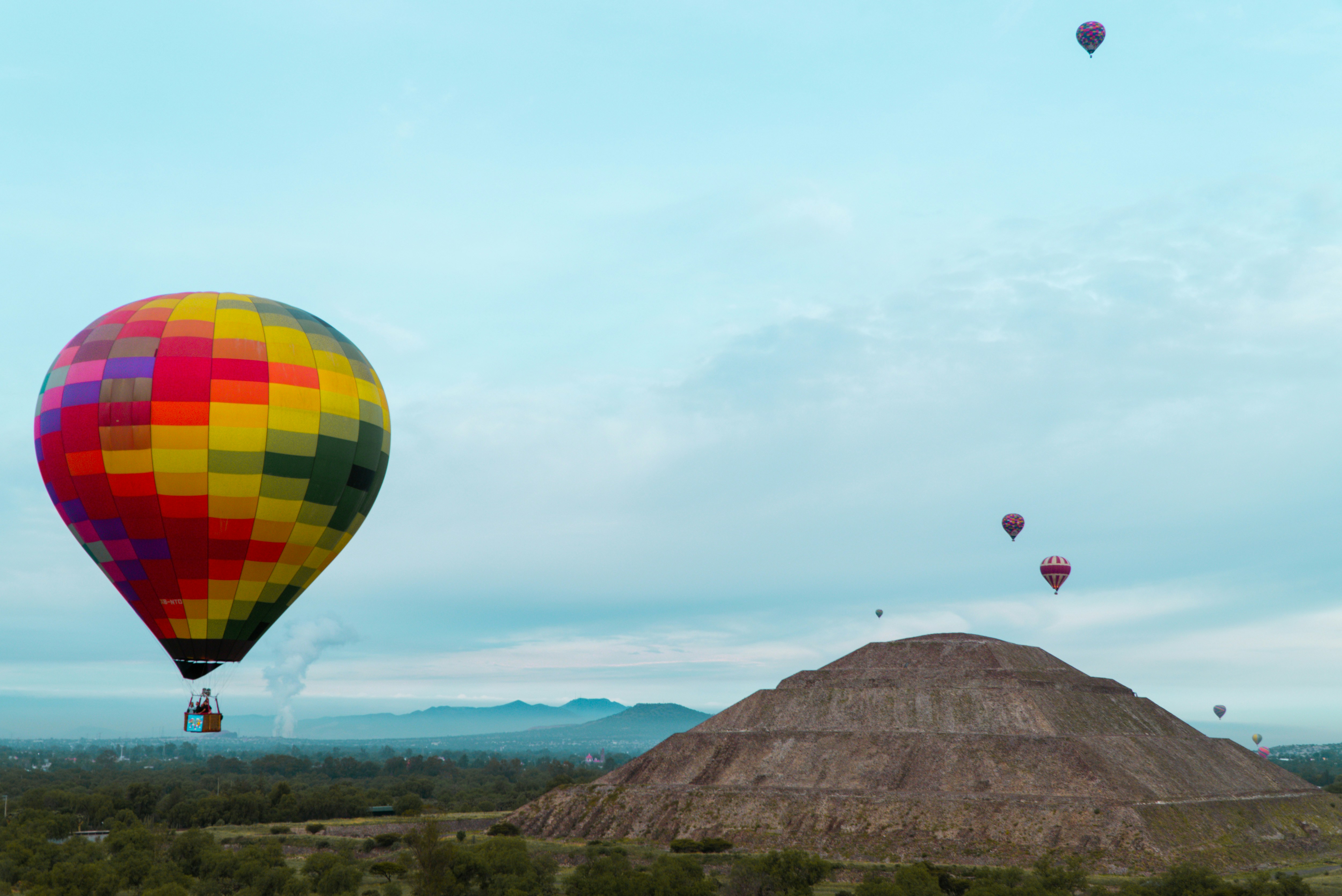 Rainbow Giant Over the Desert Mesa as Distant Balloons Drift