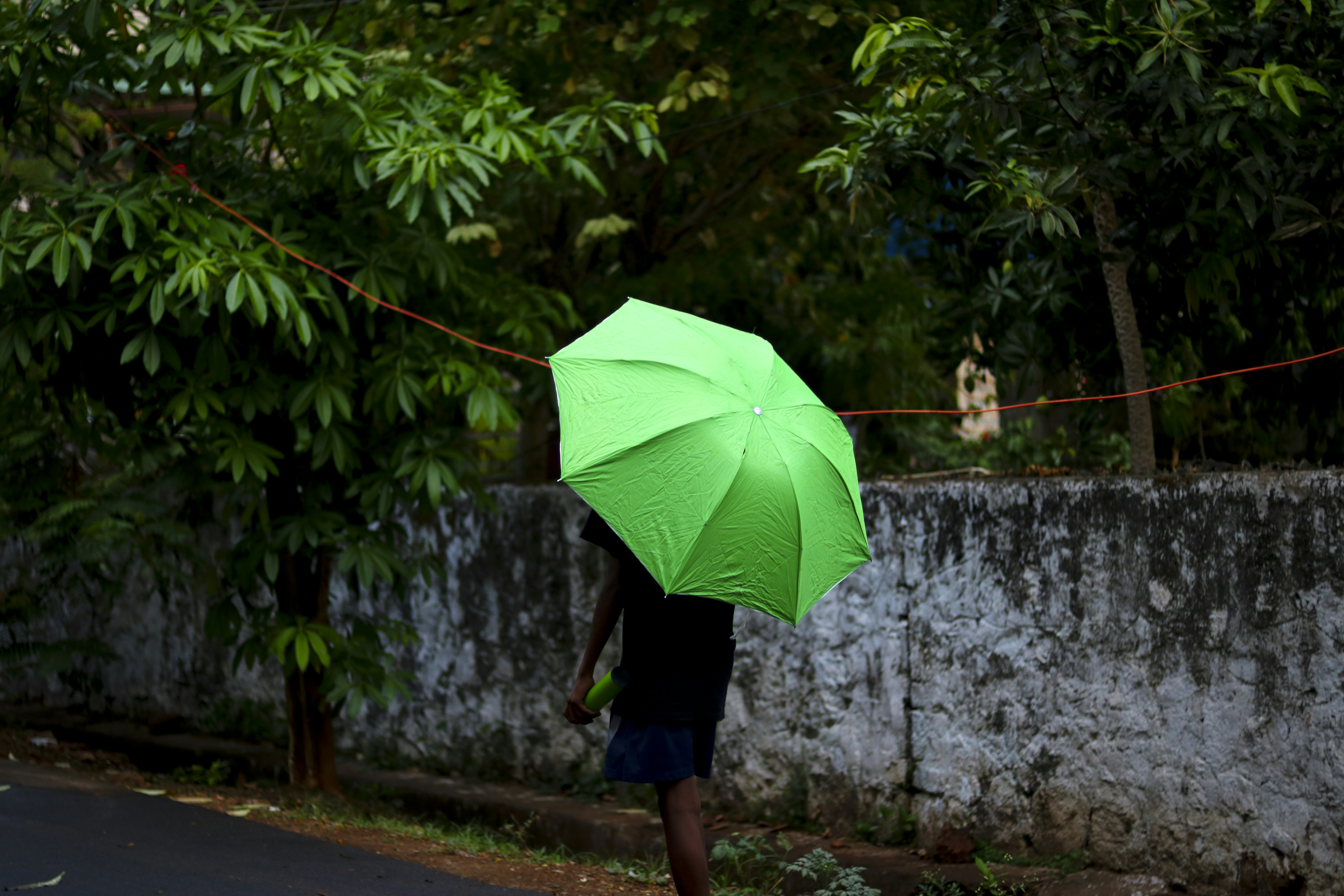 a person walking down a street with a green umbrella