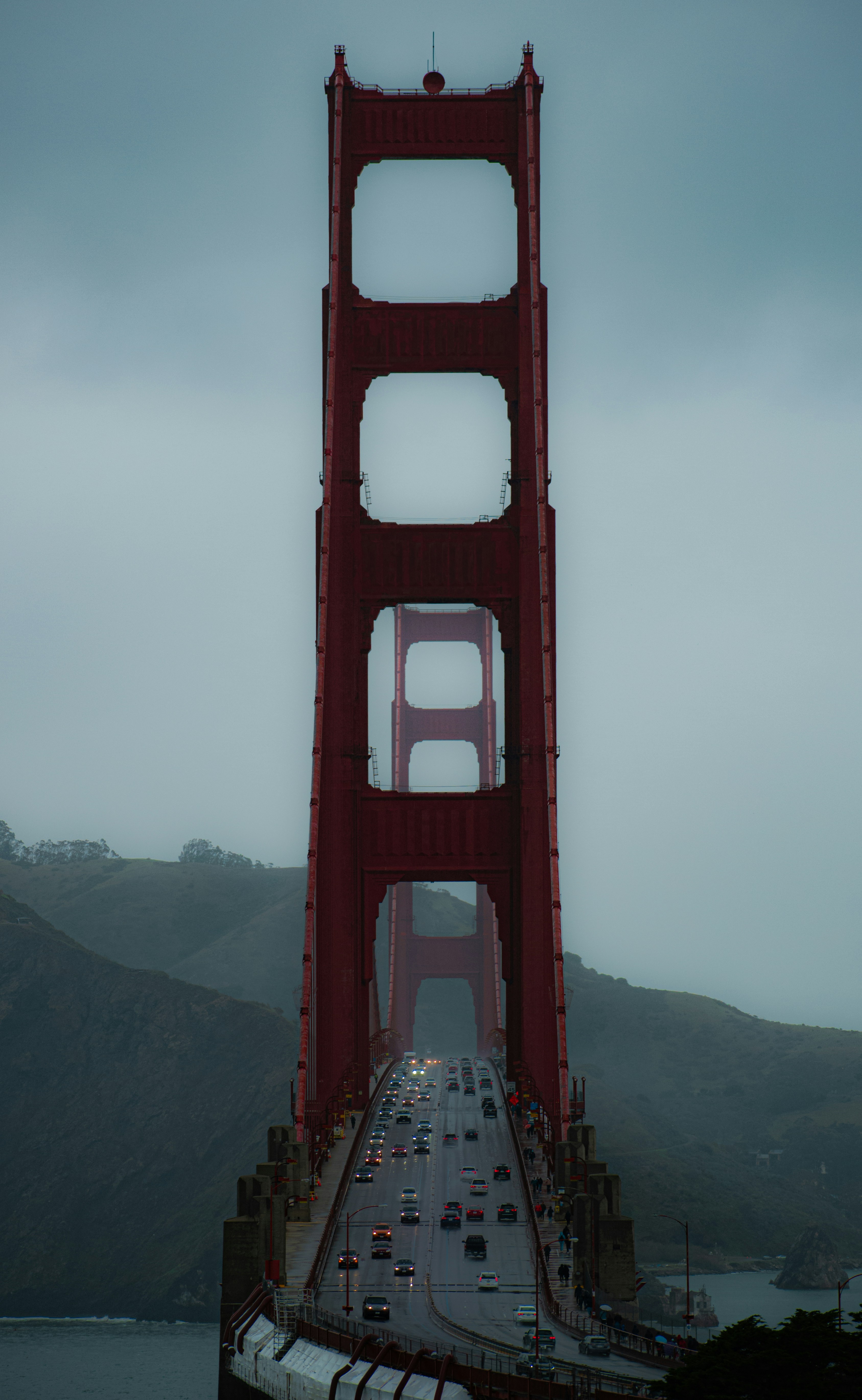 Golden Gate Bridge towering above a foggy landscape, with vehicles traversing the roadway below.