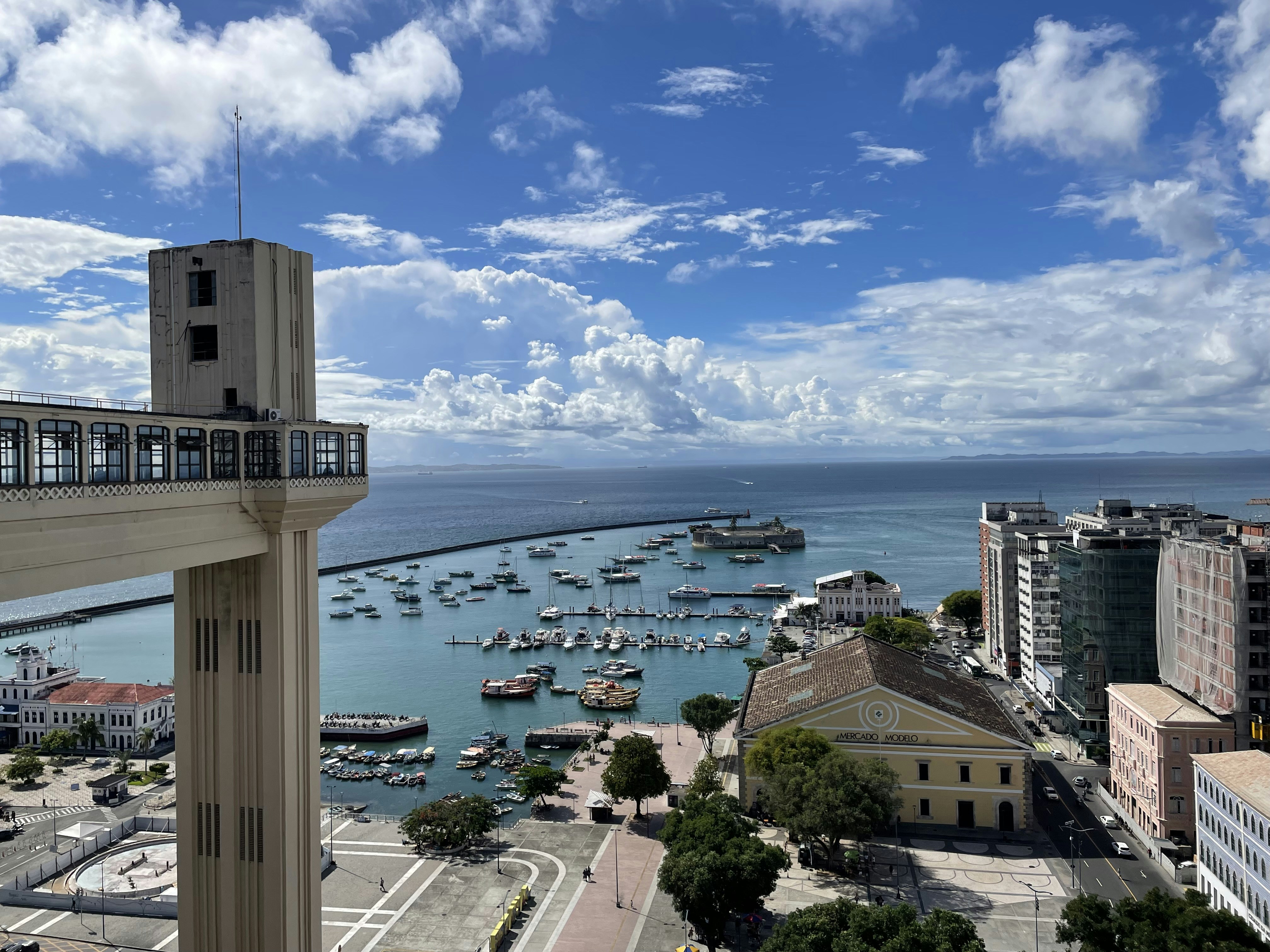 Urban harbor scene with boats anchored in calm waters beneath a cloudy sky.