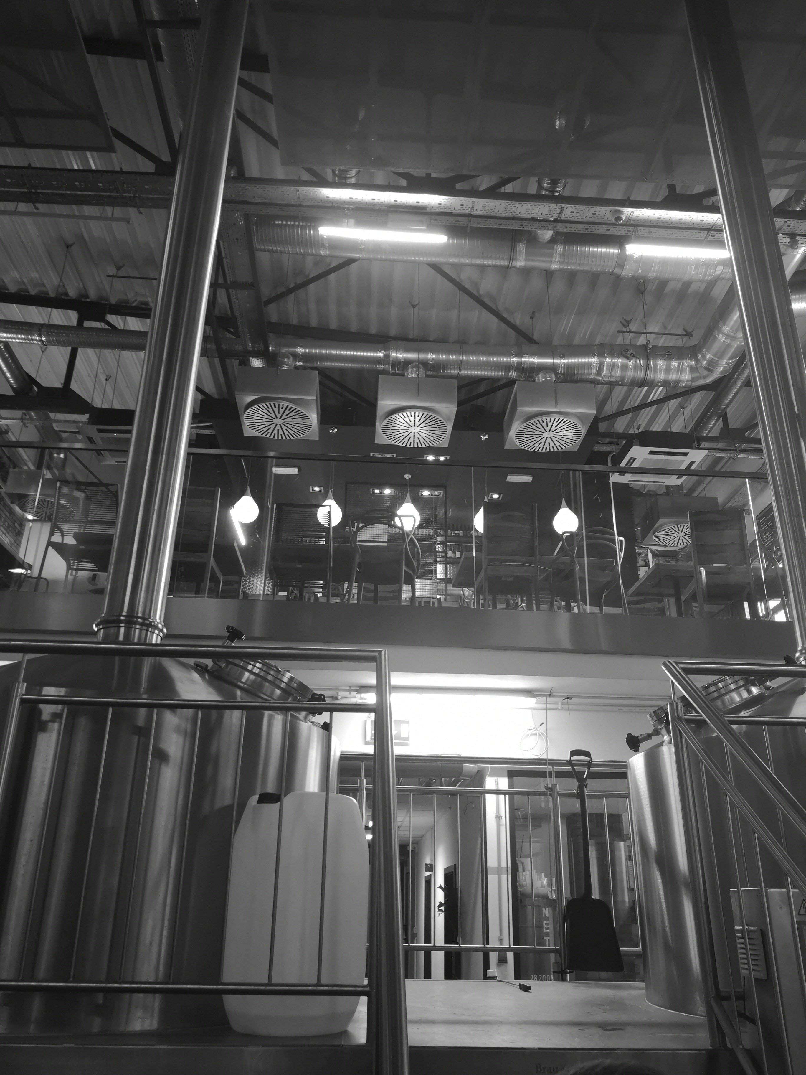 Monochrome Corridor of Steel: Tanks, Pipes, and Light Receding Into the Background