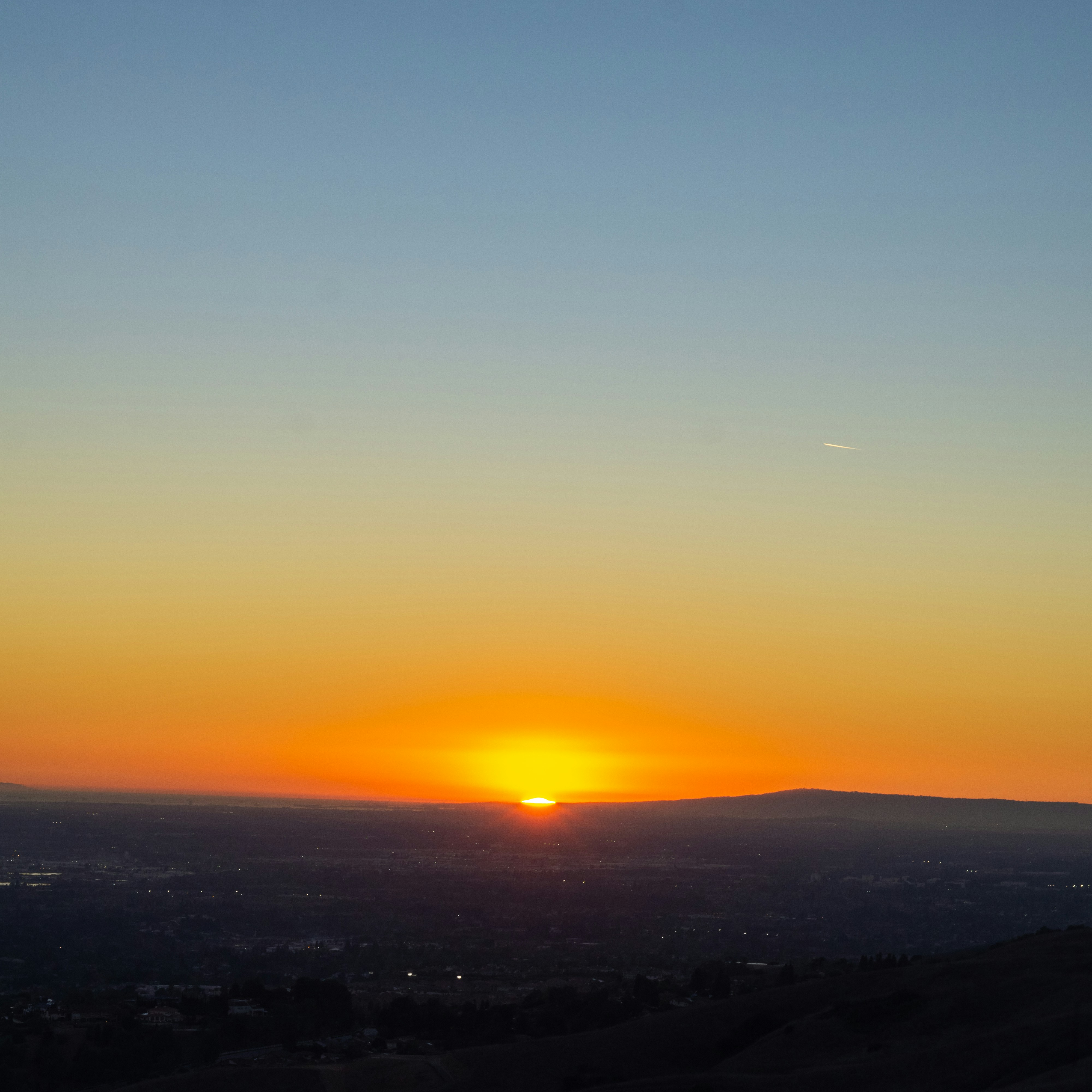 The sun is setting over a valley with hills in the background photo ...